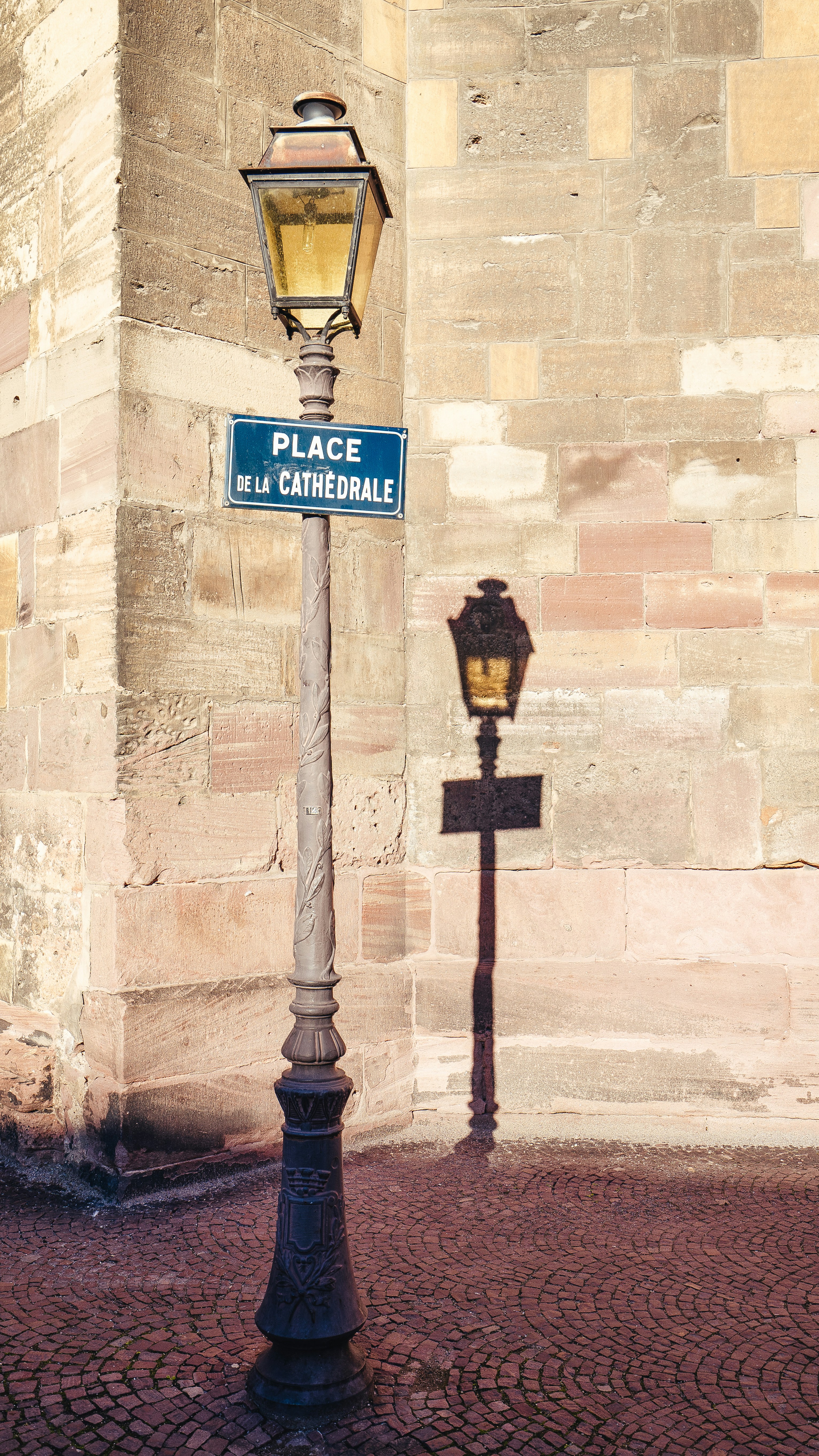 A vintage streetlamp casting a dark shadow on a stone wall