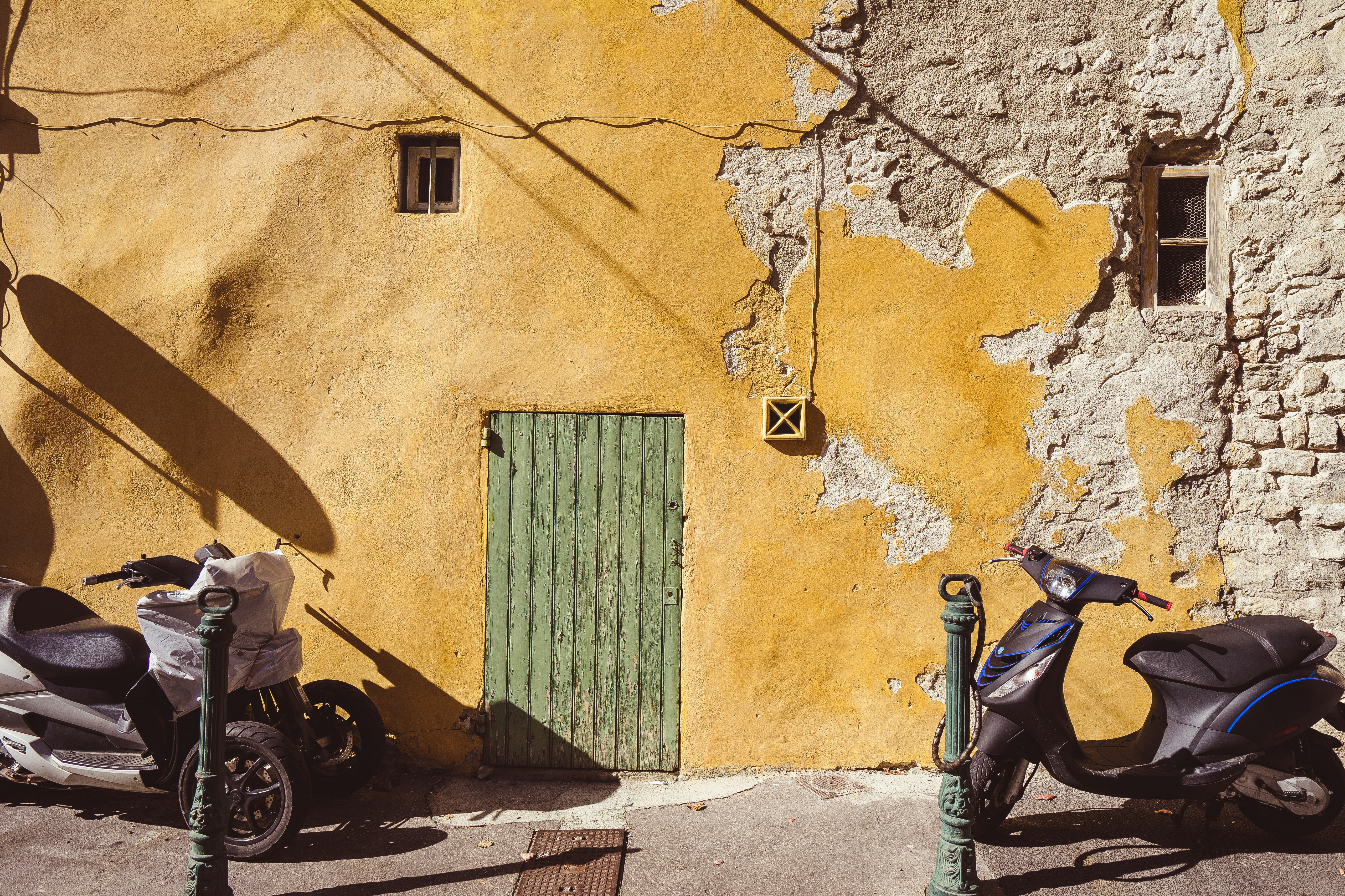 Yellow Wall and Green Door: A Quiet Street Corner with Scooters