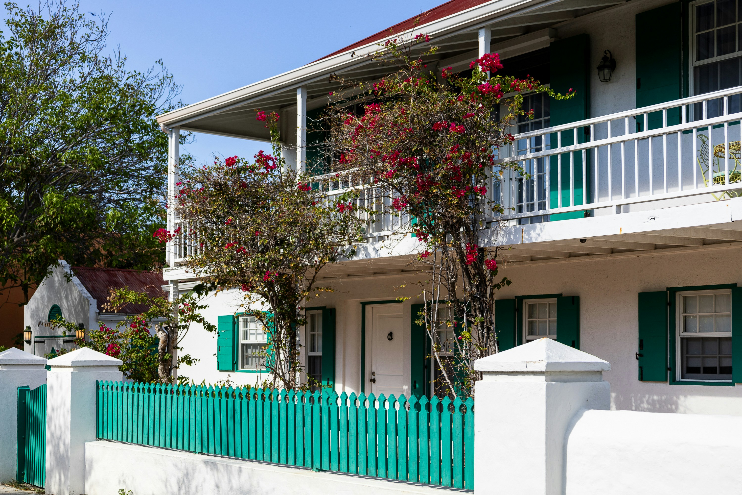 Courtyard Bloom: A Coral-Flowered Balcony Beneath Turquoise Shutters