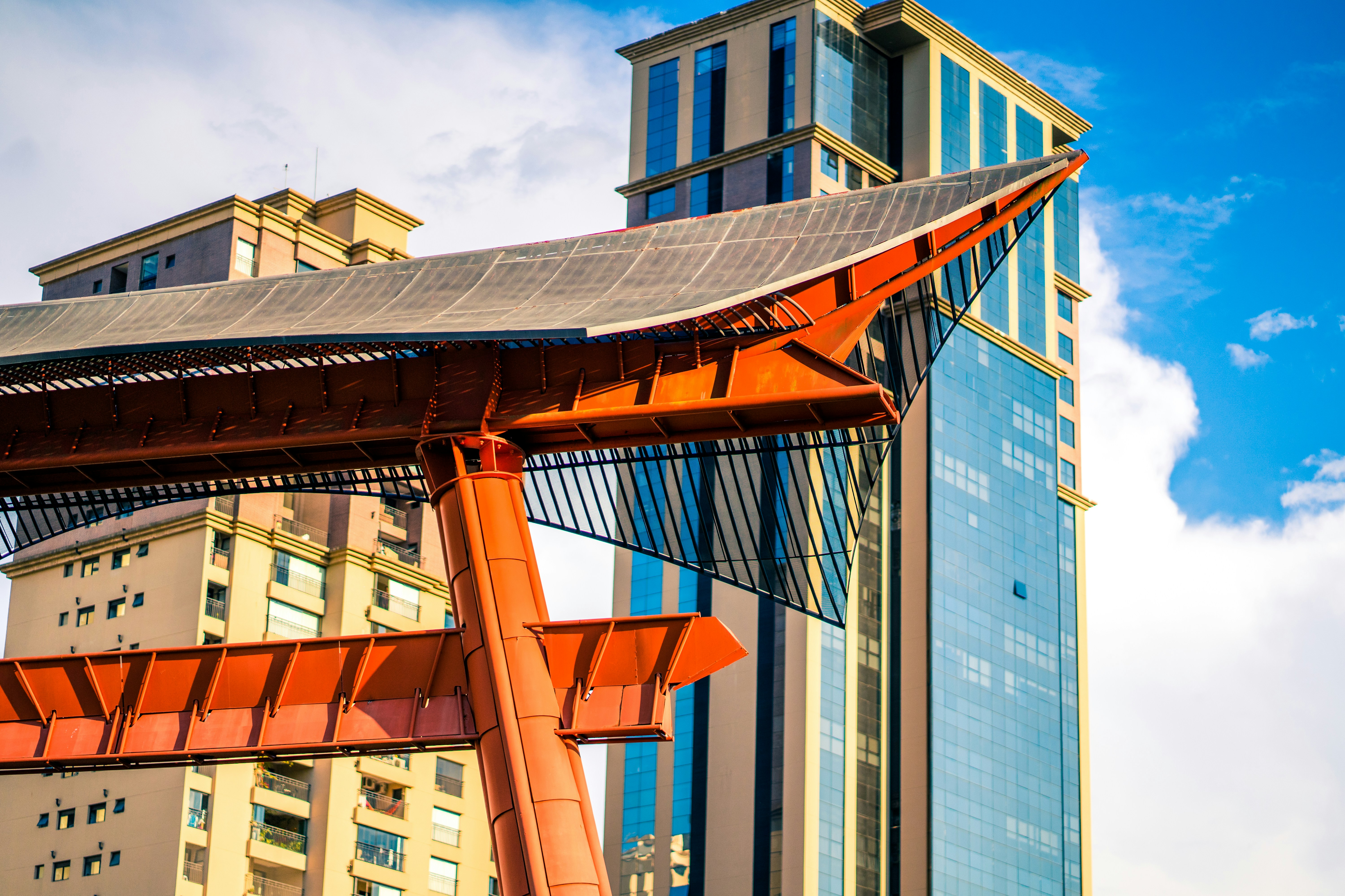 Urban Geometry: A Steel-Red Arc Framing a Skyward Glass Tower