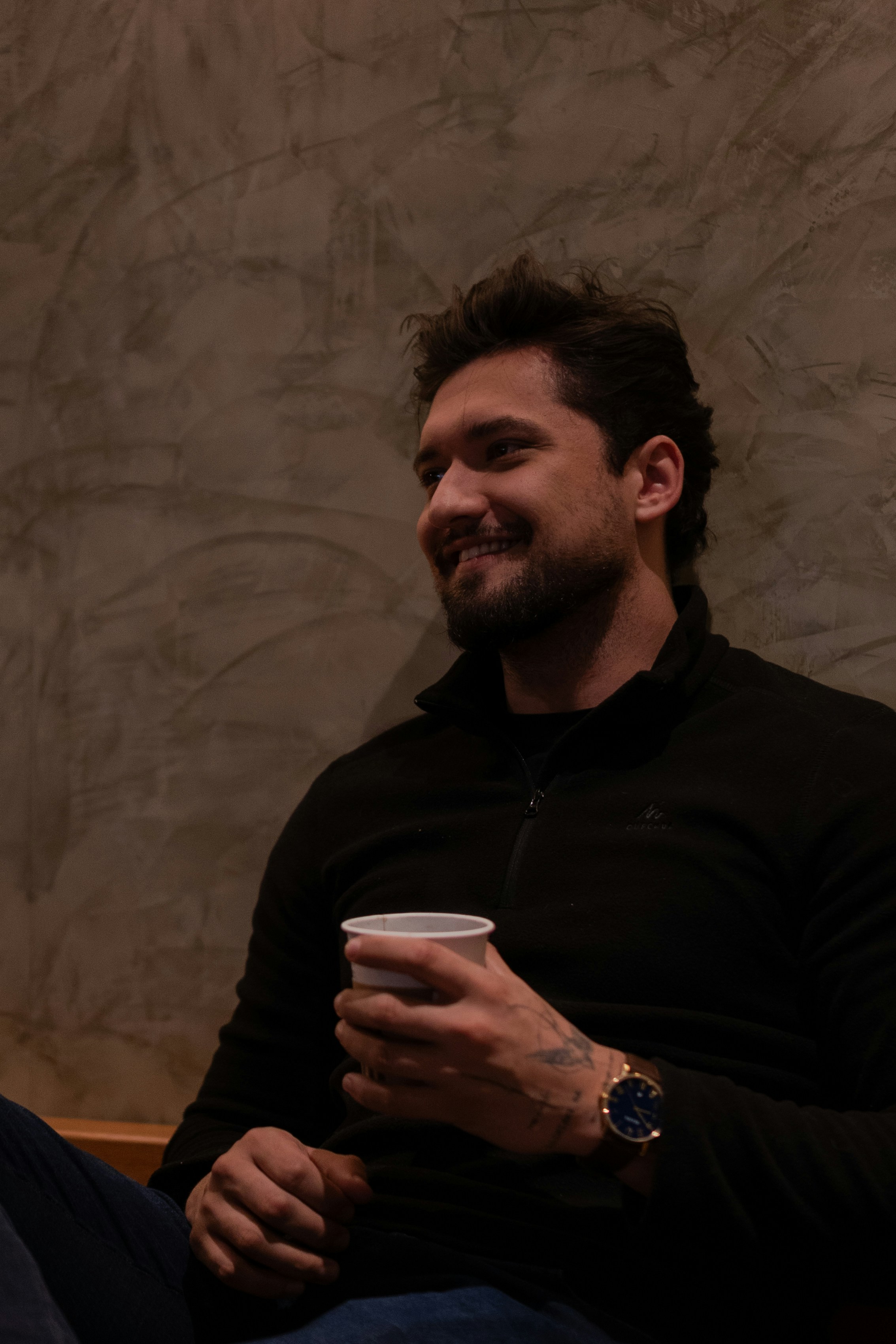 Relaxed Confidence: A Man with a Cup in Low Light