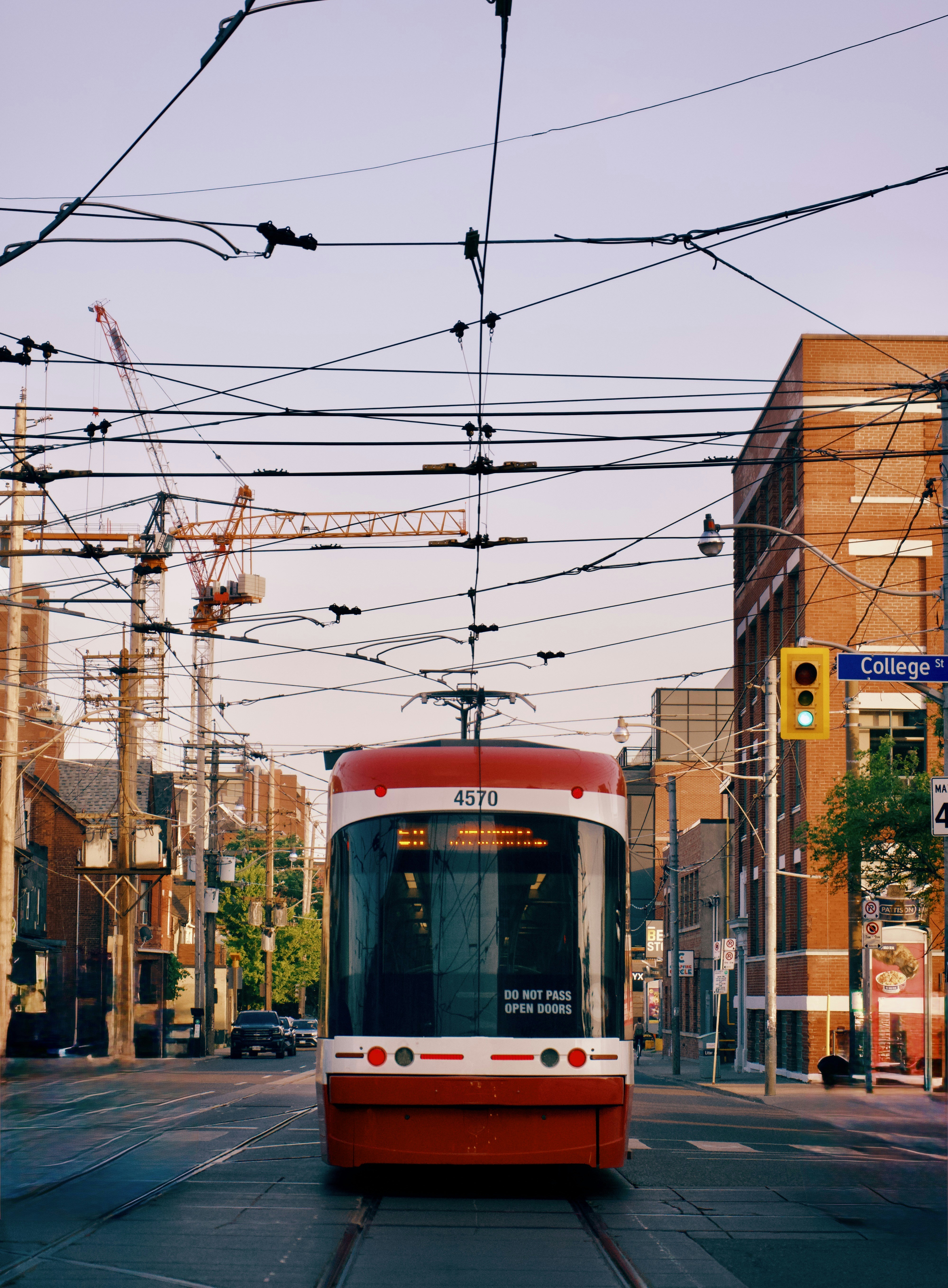 A red streetcar on tracks at the College Street intersection in Toronto