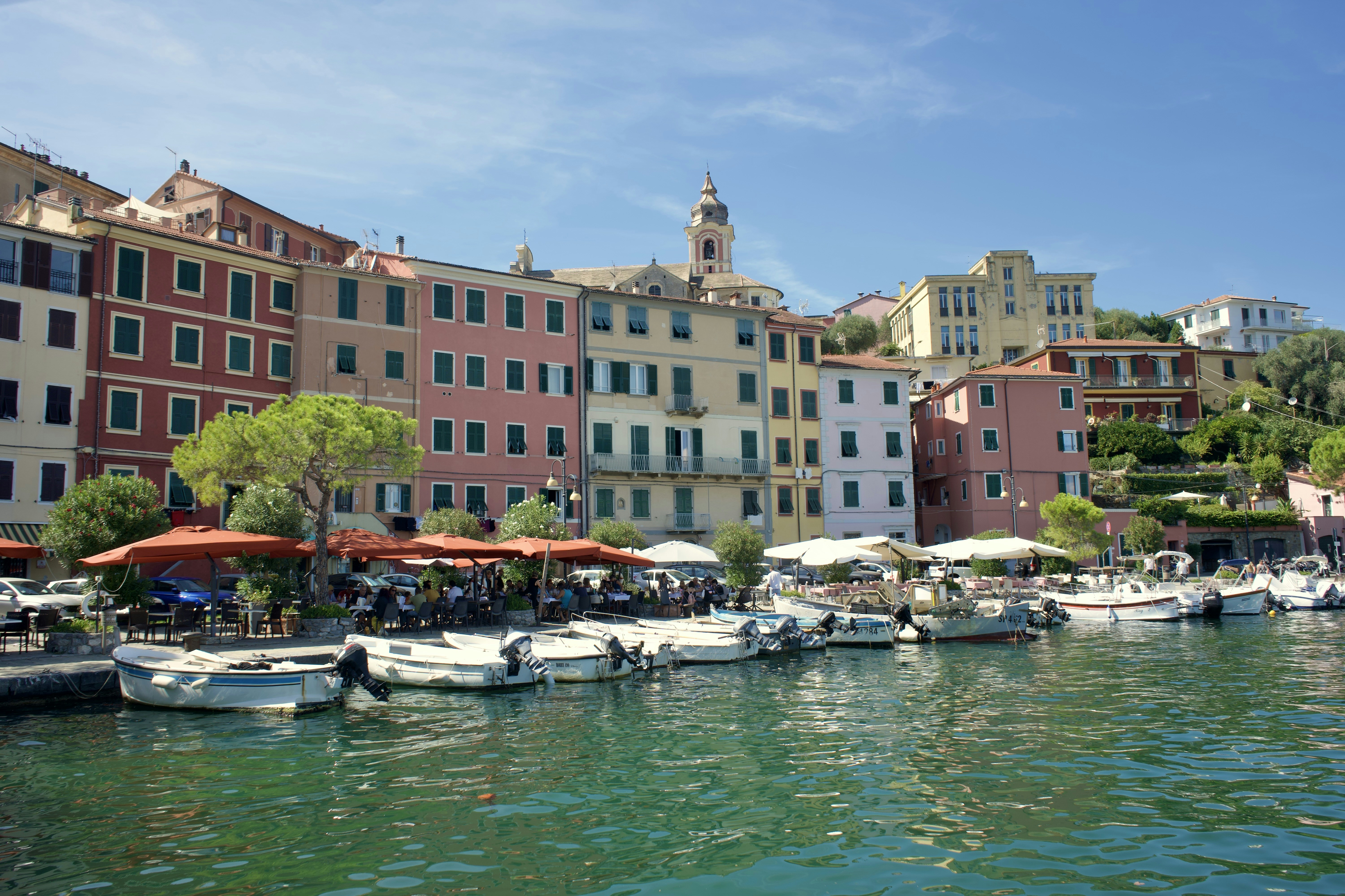 Colorful harbor town along turquoise waters with boats and awning-clad waterfront