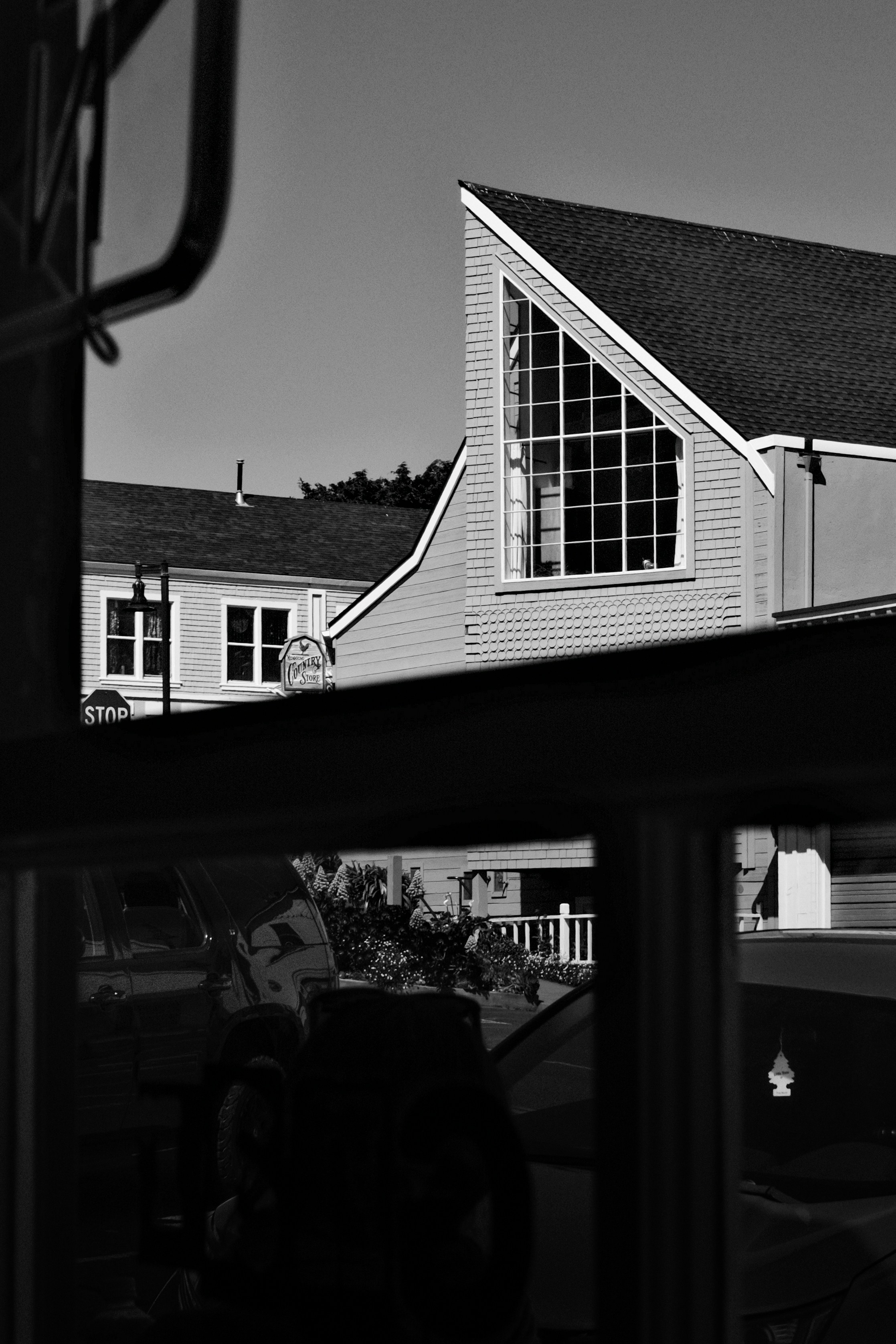 Architectural Echoes: A Black-and-White Street Scene Framed by Glass and Gables
