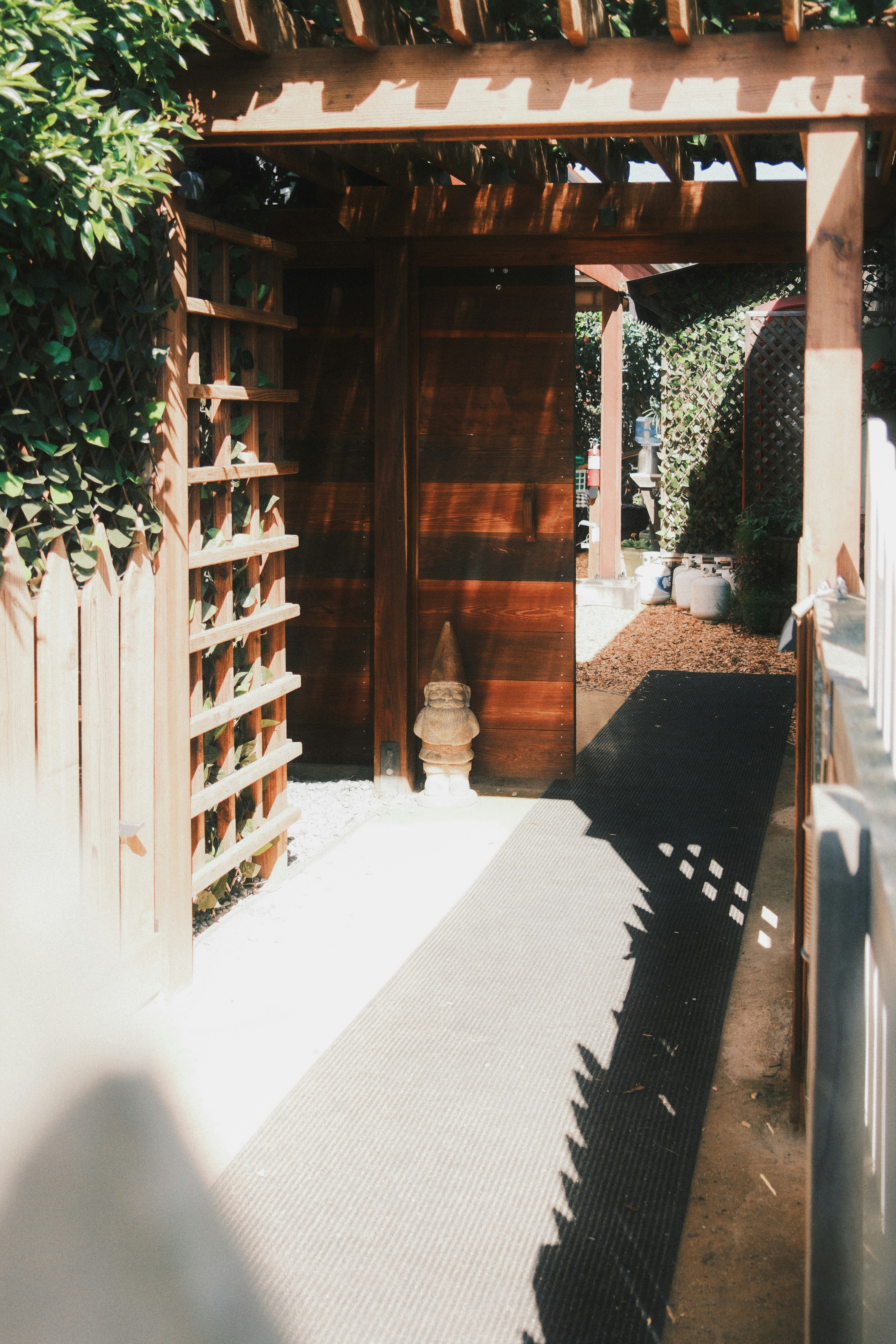 Wooden Gate Corridor: Sunlit Path Through an Engraved Arch