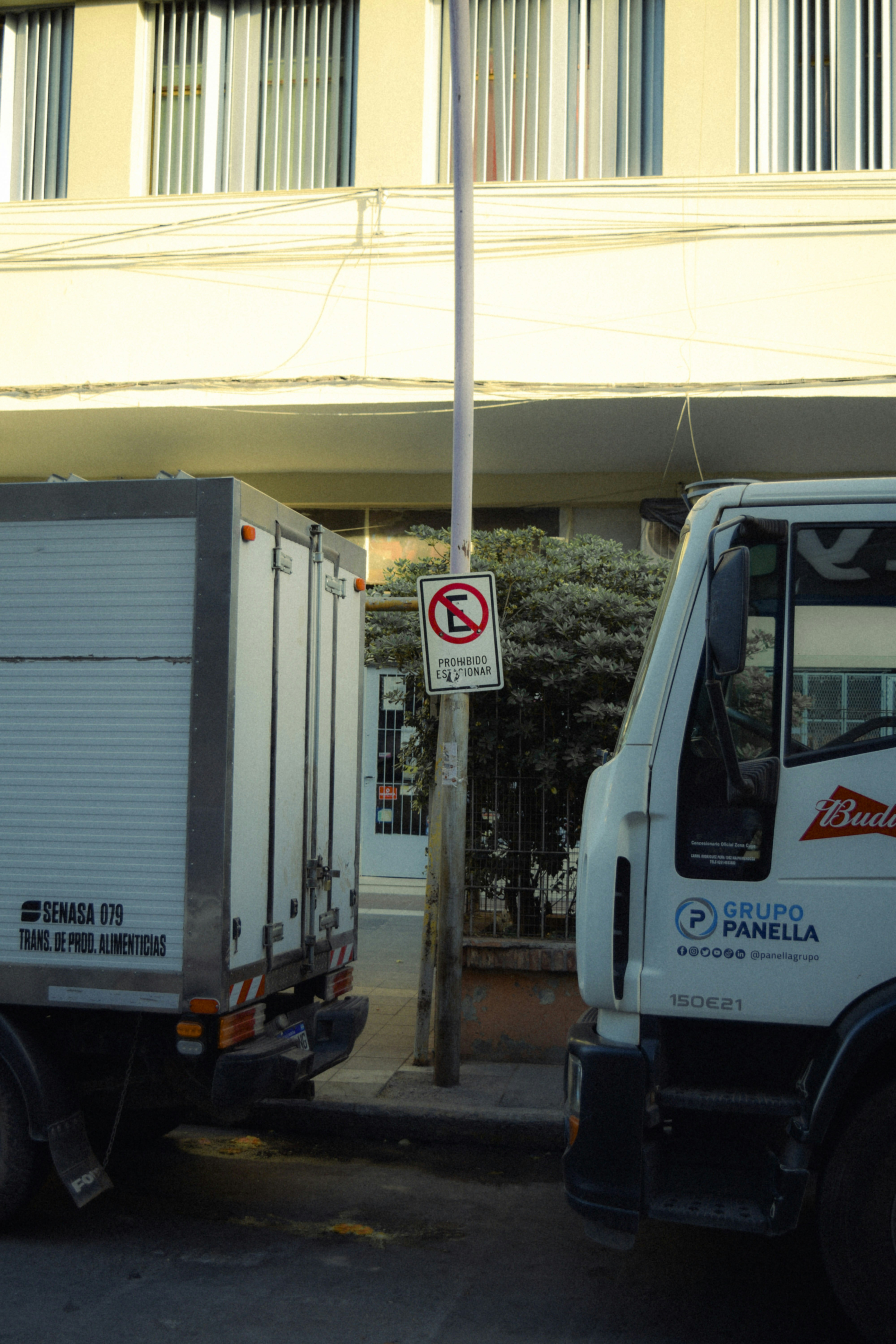 Vehicles at a Narrow Urban Street Under a Pale Building