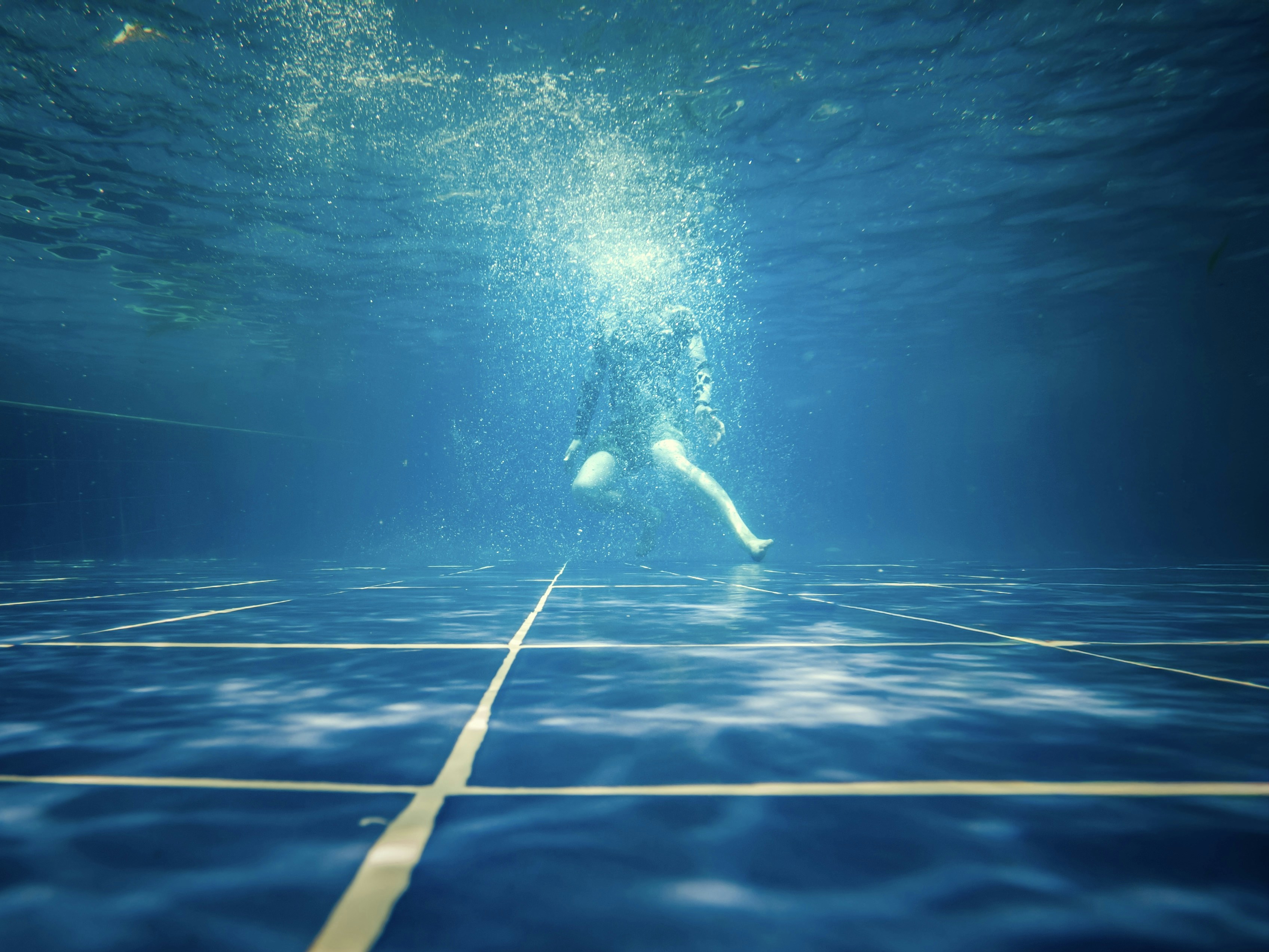 Submerged Runner: a lone diver glides beneath the lane lines