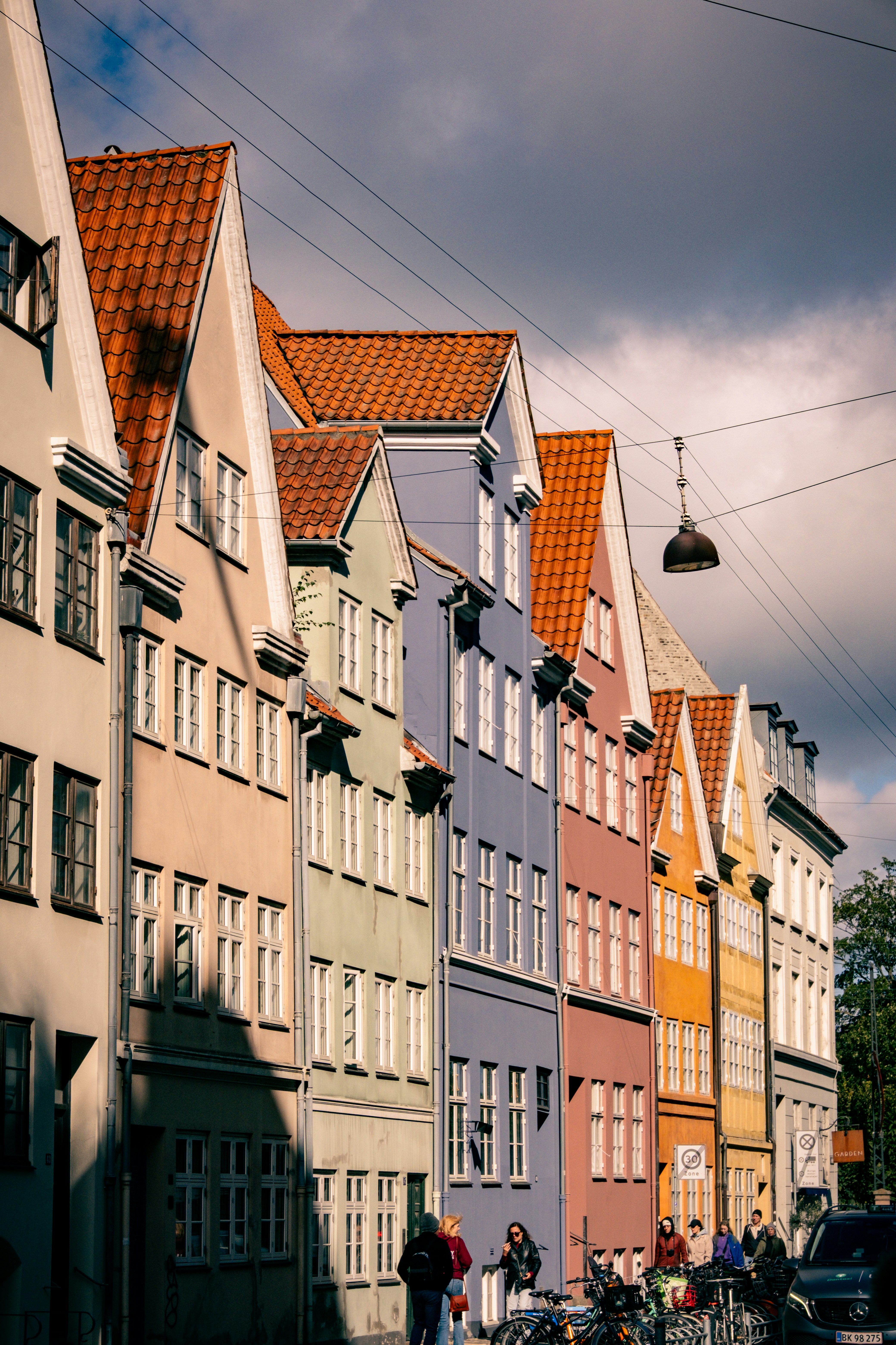 Row of pastel townhouses under a brooding sky