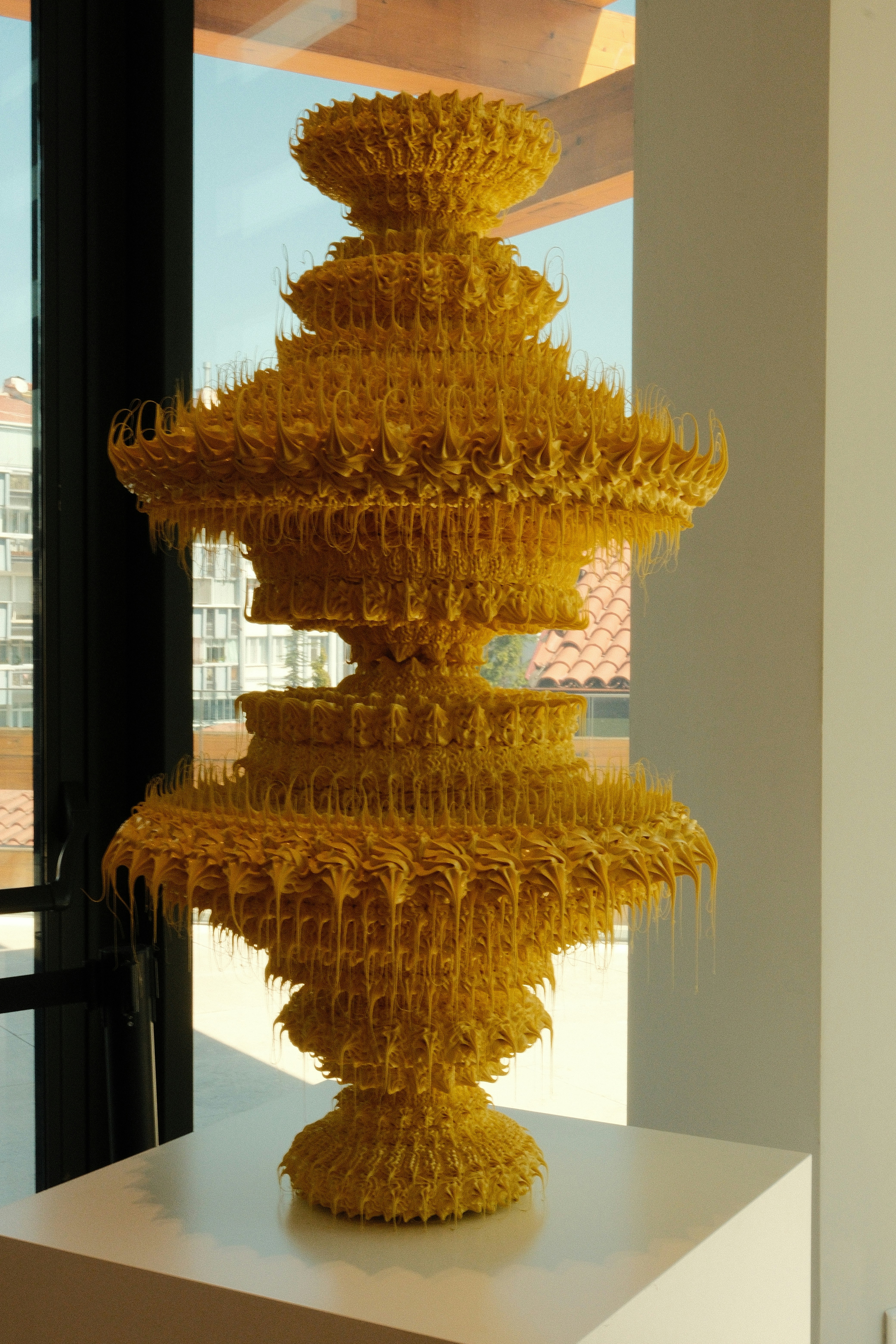 Amber Cascade: A Golden Chandelier Sculpture in Sunlit Studio