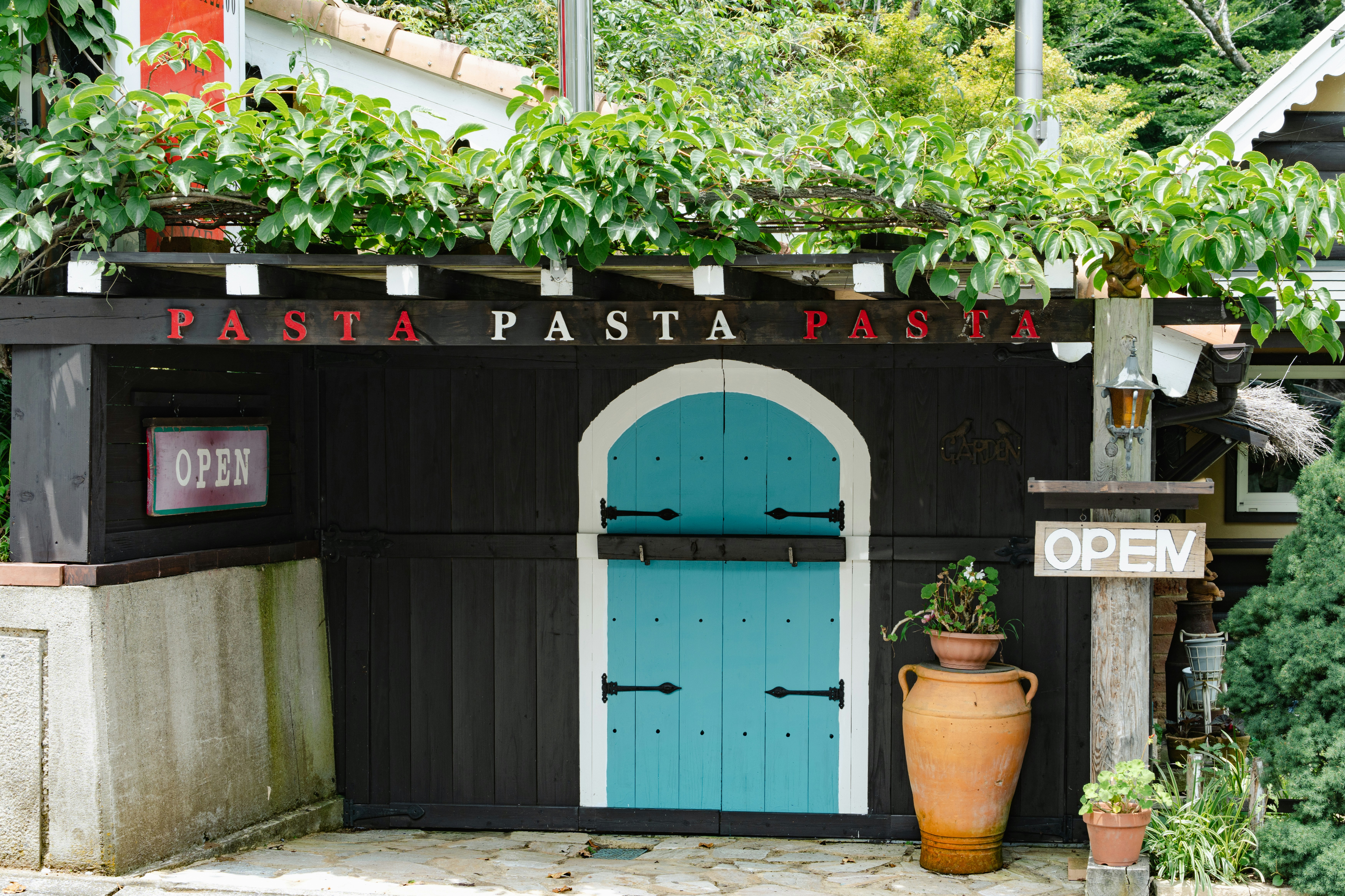 Turquoise-arched Doorway Under a Shaded Lattice of Greenery