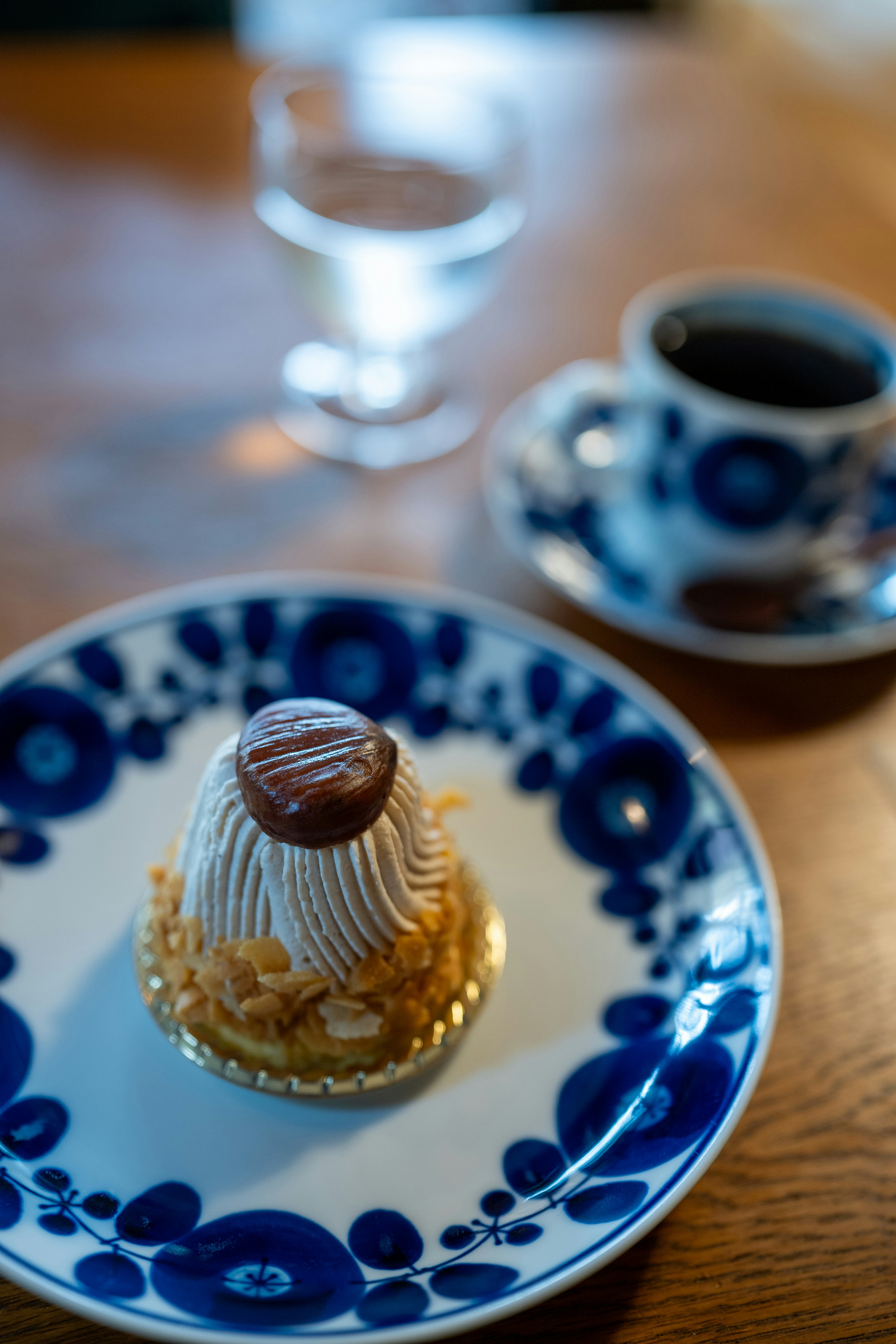 Almond-topped dessert on a cobalt plate with a blurred coffee scene