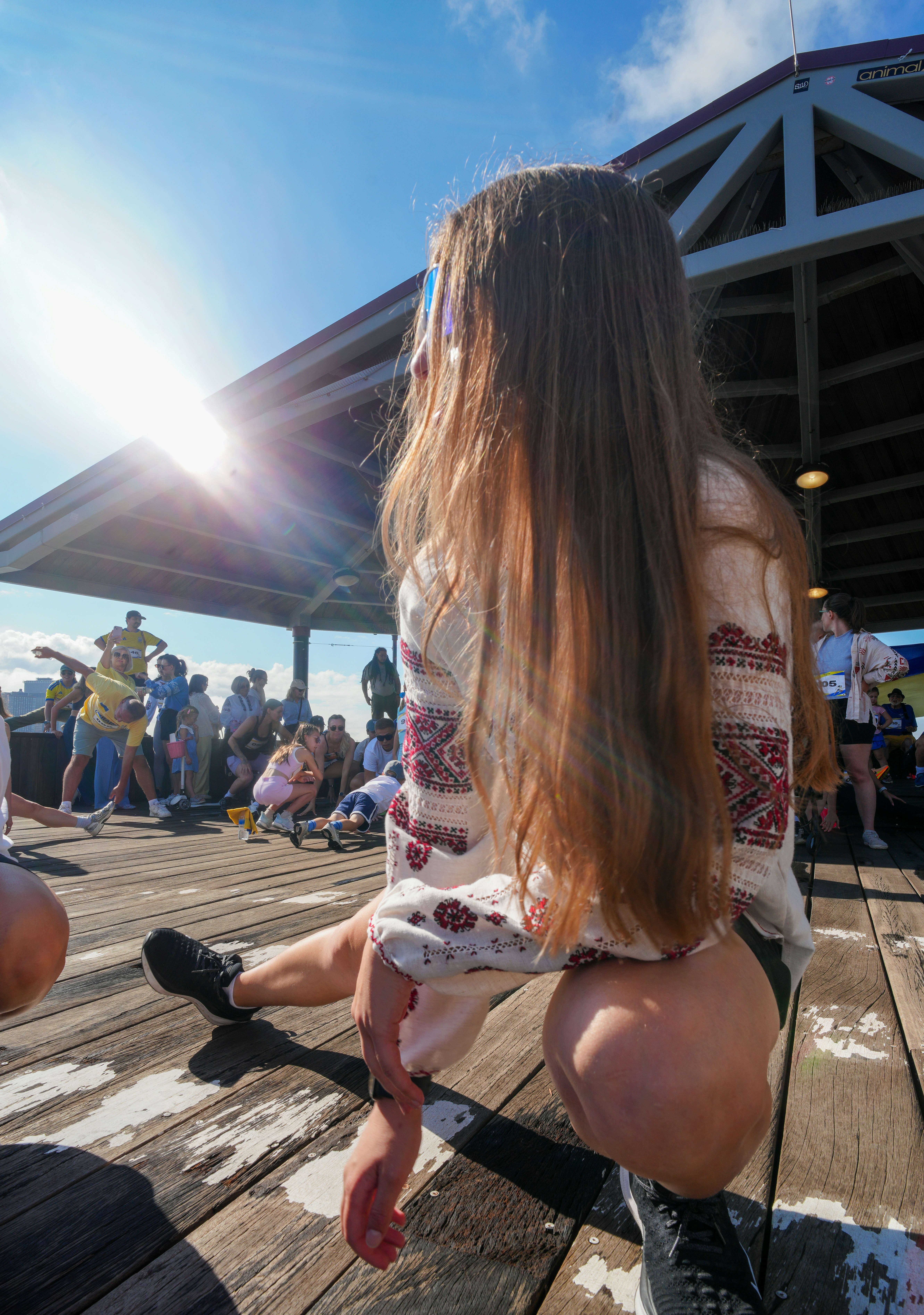 Sunlit Beachfront Dance: A Hidden Smile Amid the Boardwalk Crowd