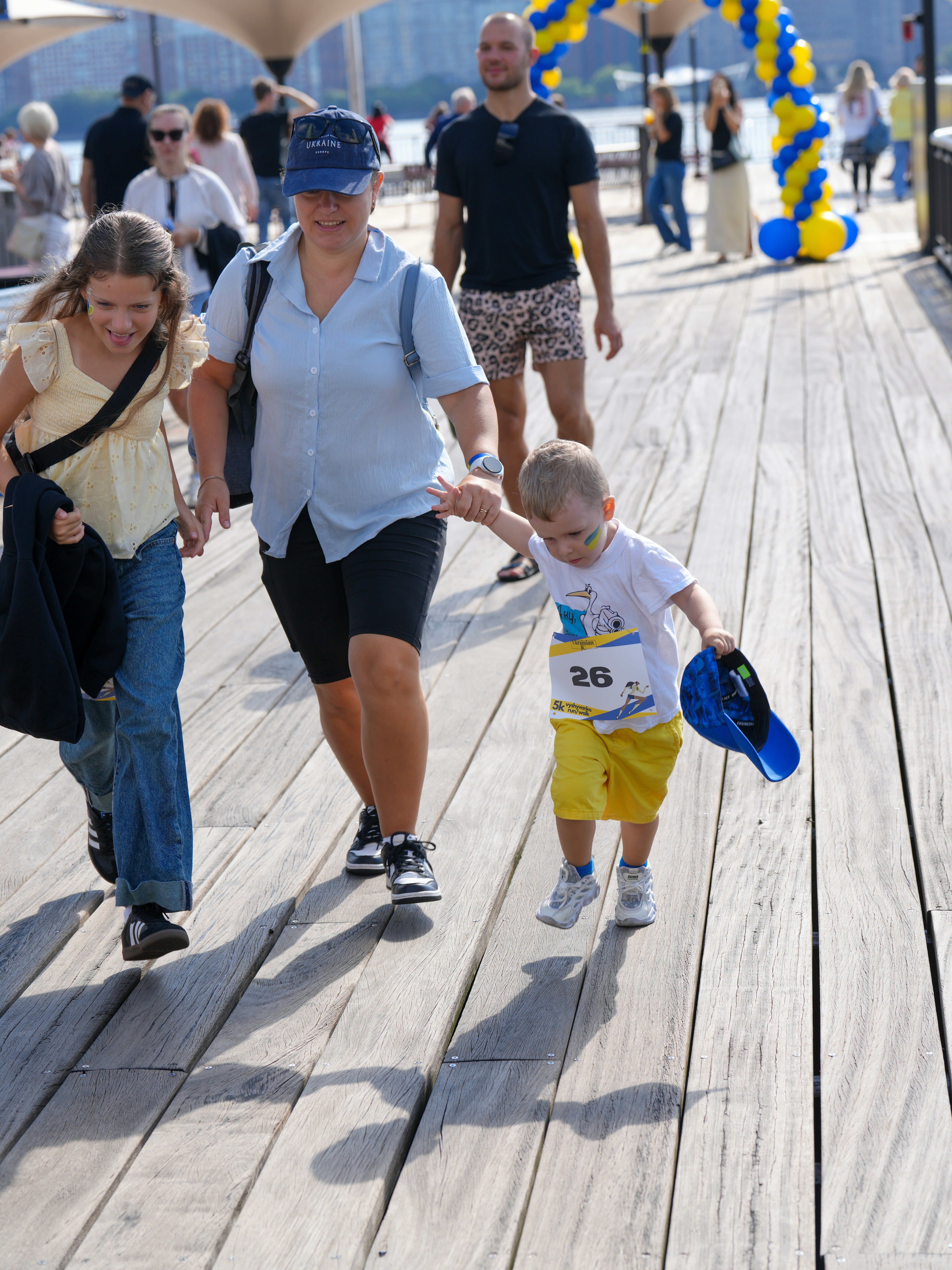 Family on a sunlit boardwalk race, guided by a determined little racer