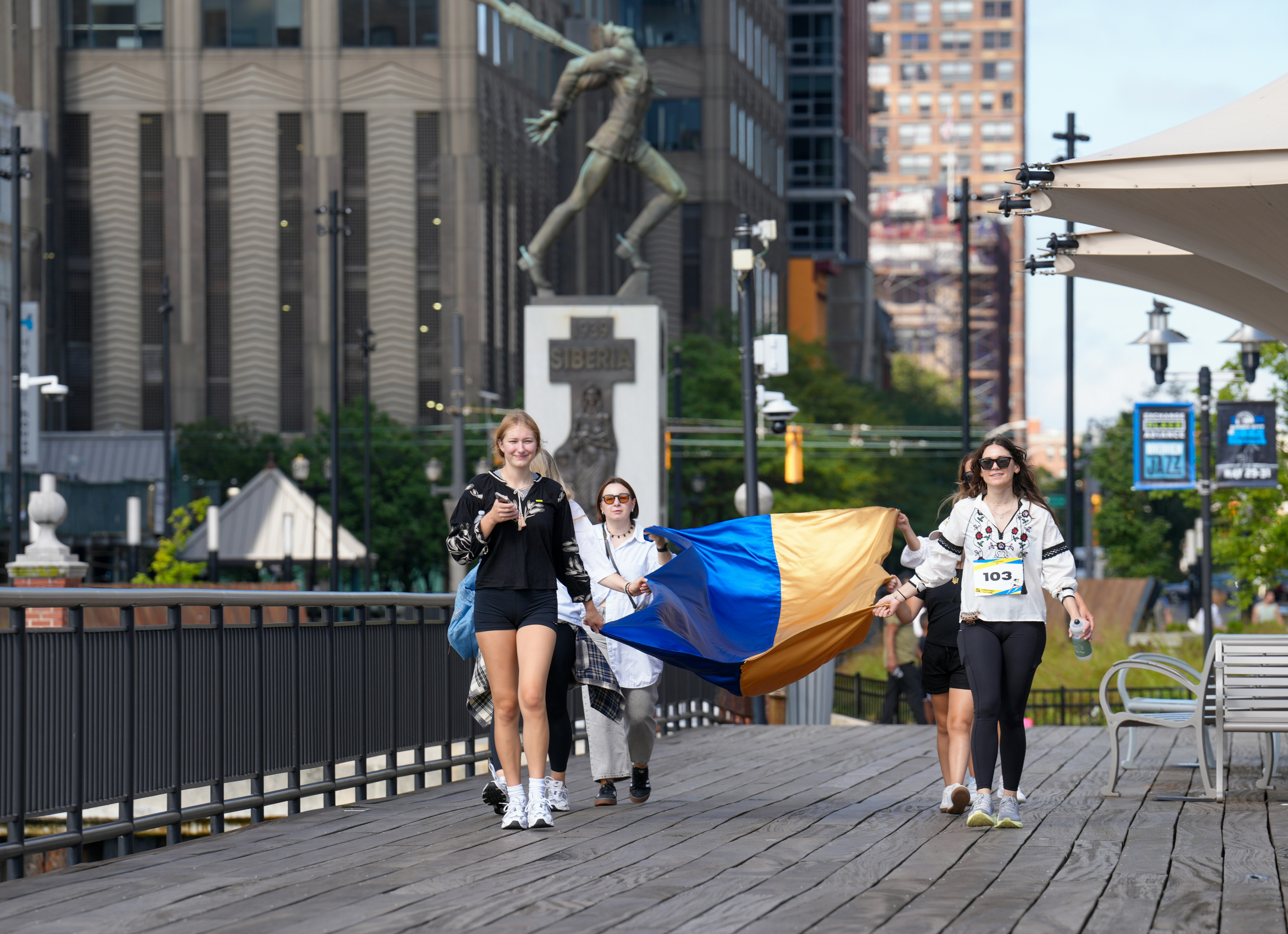A Lantern of Freedom: Friends Carry a Ukrainian Flag Along a Riverside Boardwalk