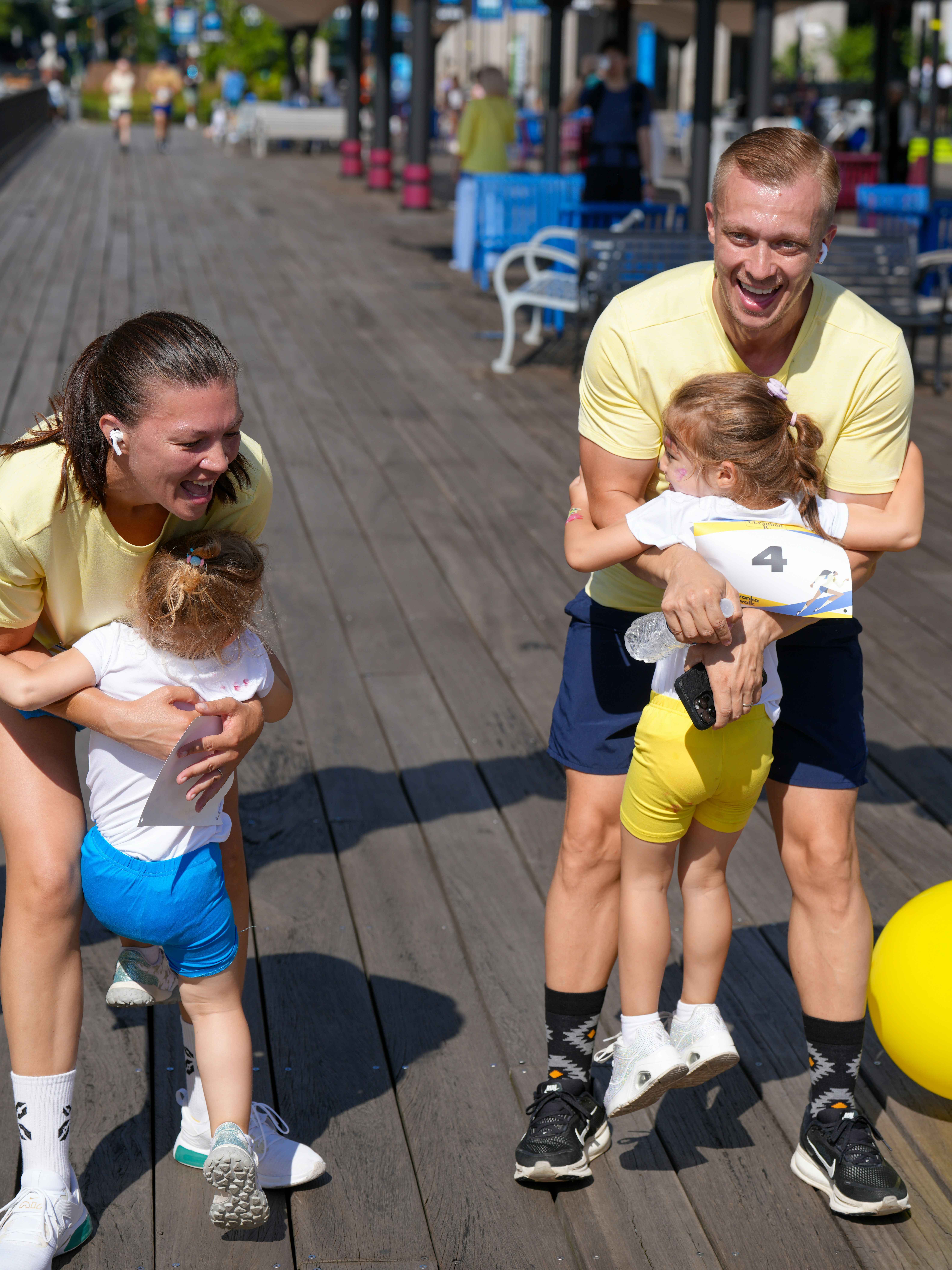 Joyful Family Run: Adults Lift Kids in a dockside race moment