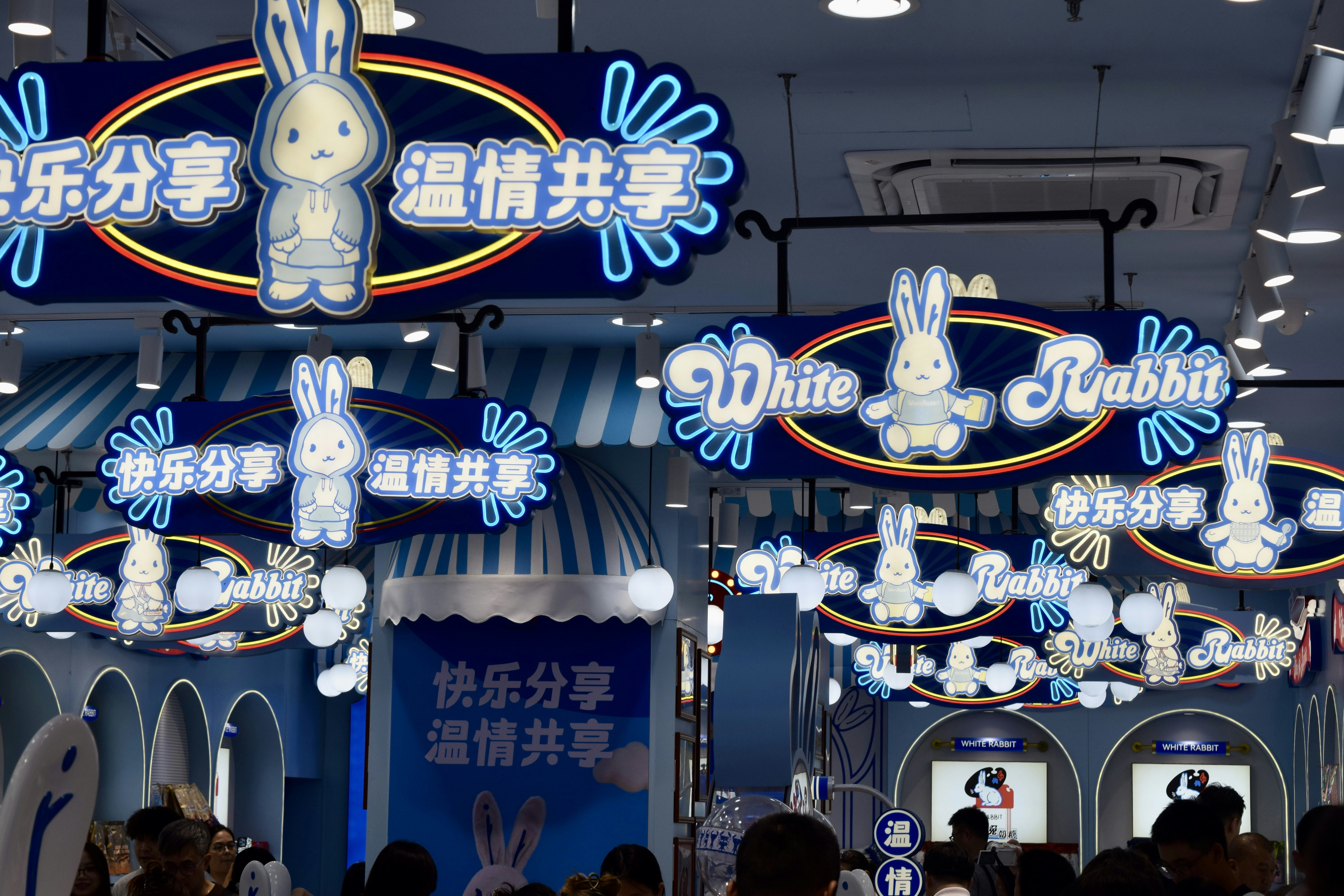 Rabbit Neon: A Carousel of Blue Signage in a Busy Arcade