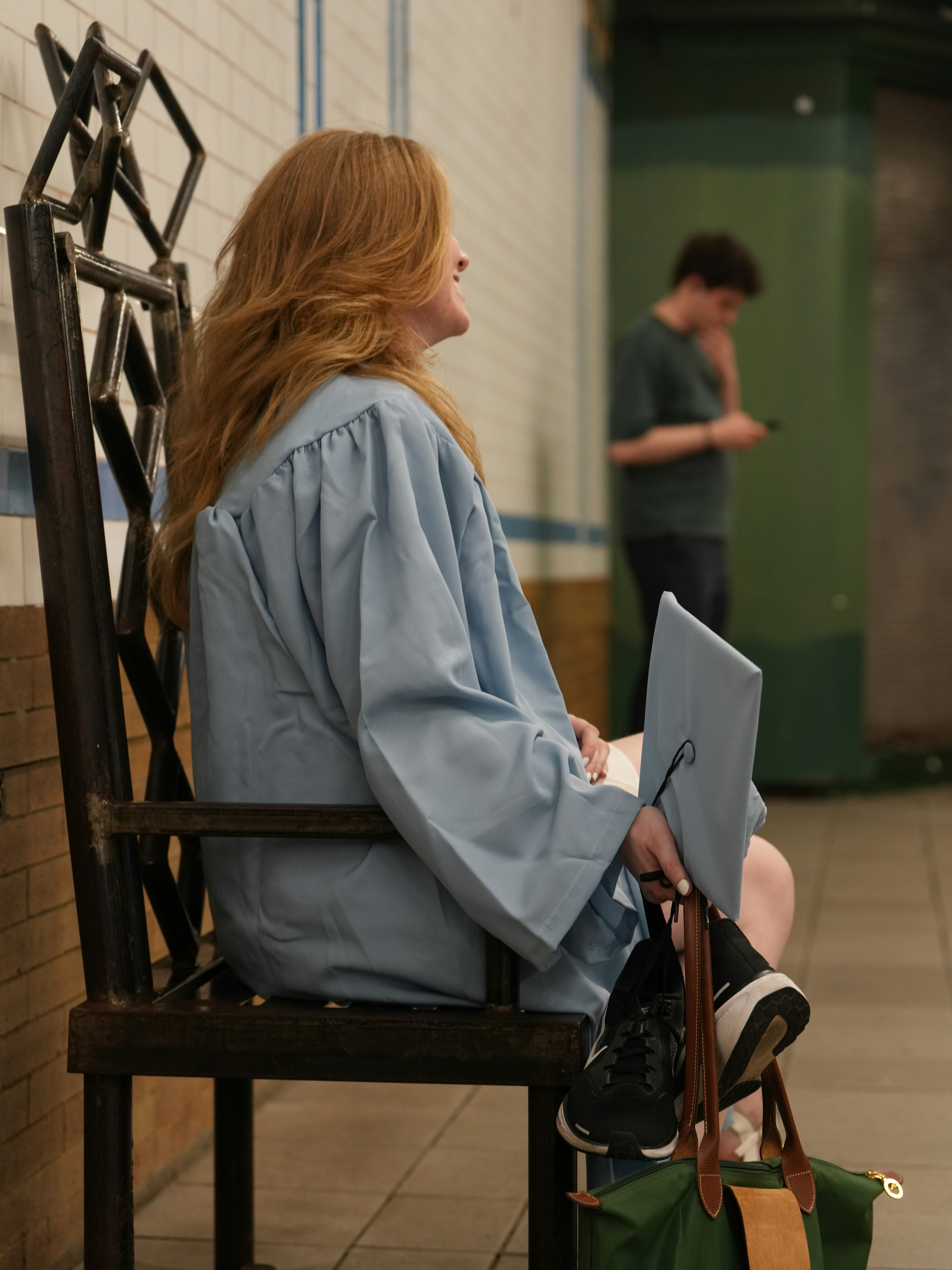 Quiet waiting moment: student in blue gown on a tiled platform