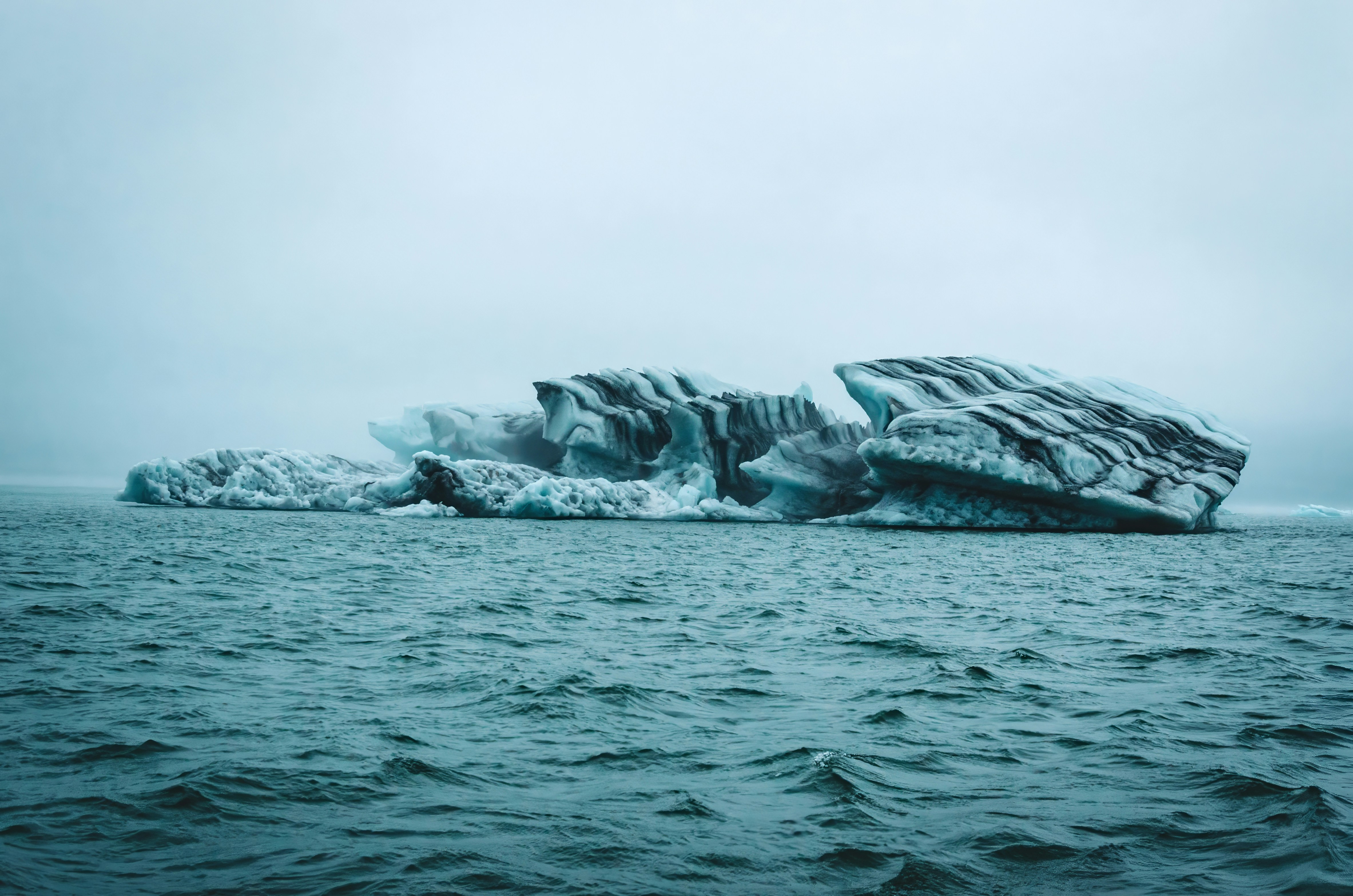 Icebound Sentinel: A Lone Iceberg Drifting under a Pale Sky