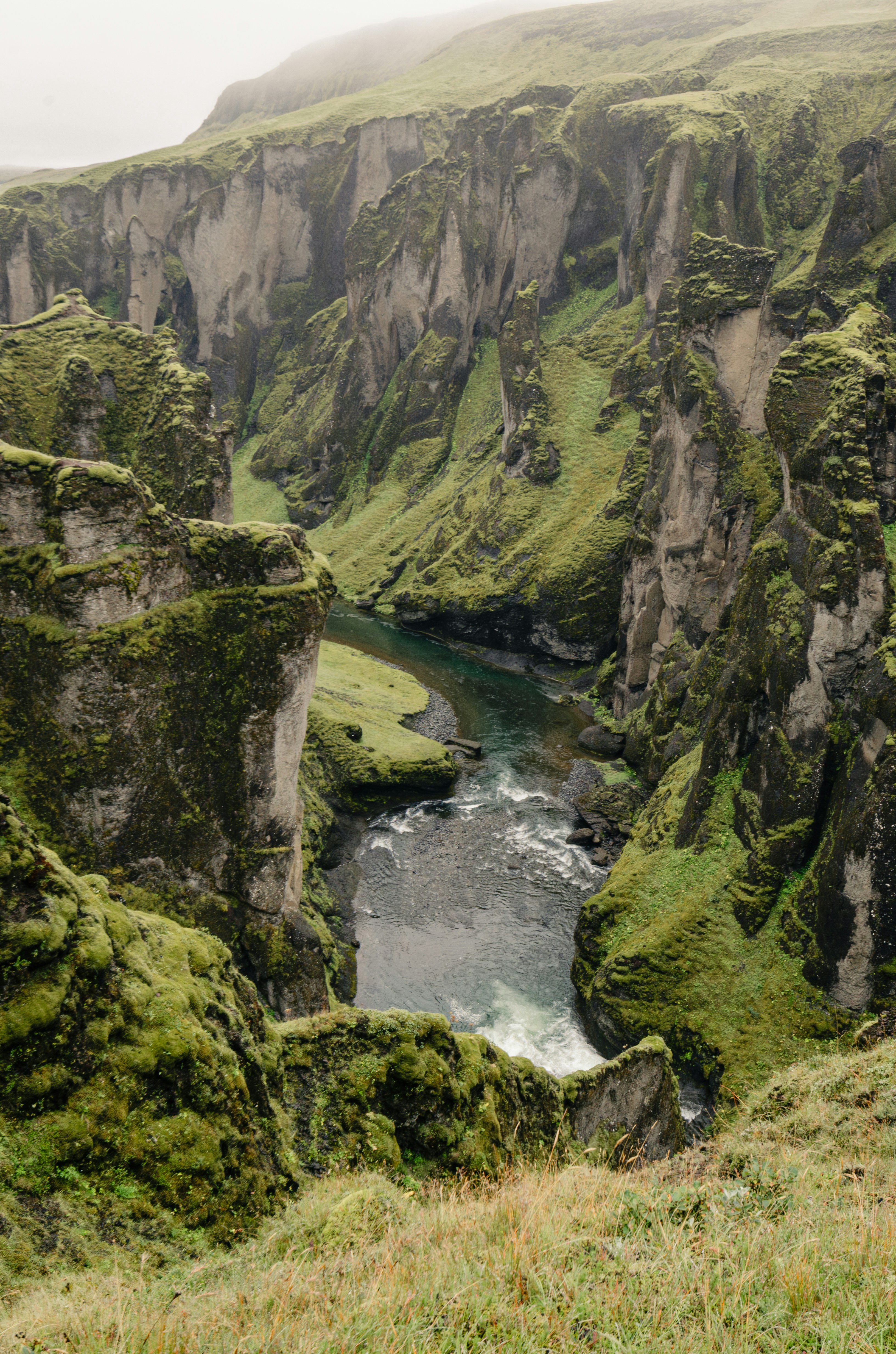 Moss-clad chasm: a misty river threads through basalt cliffs