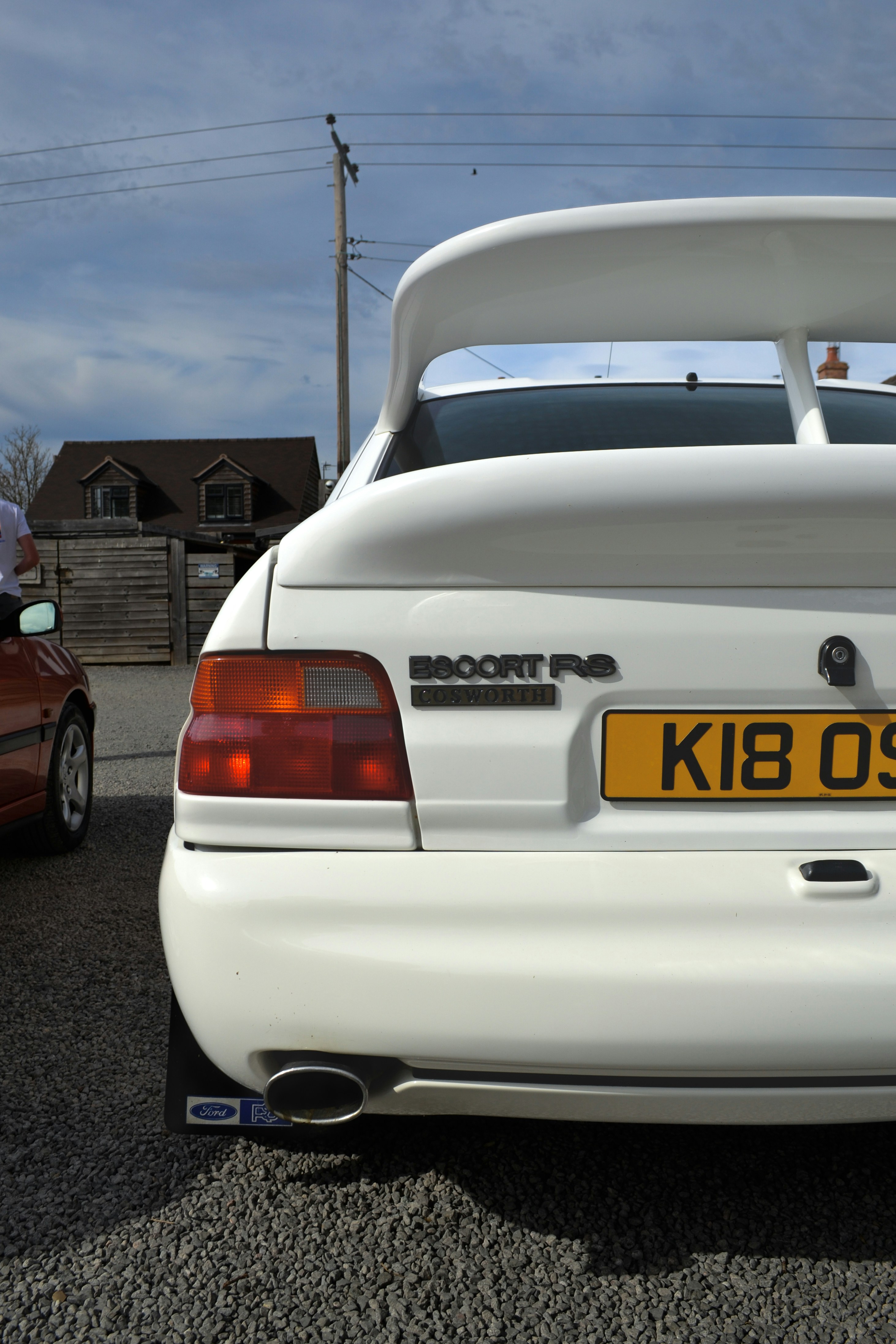 Rear badge and spoiler of a white performance sedan in a parking lot
