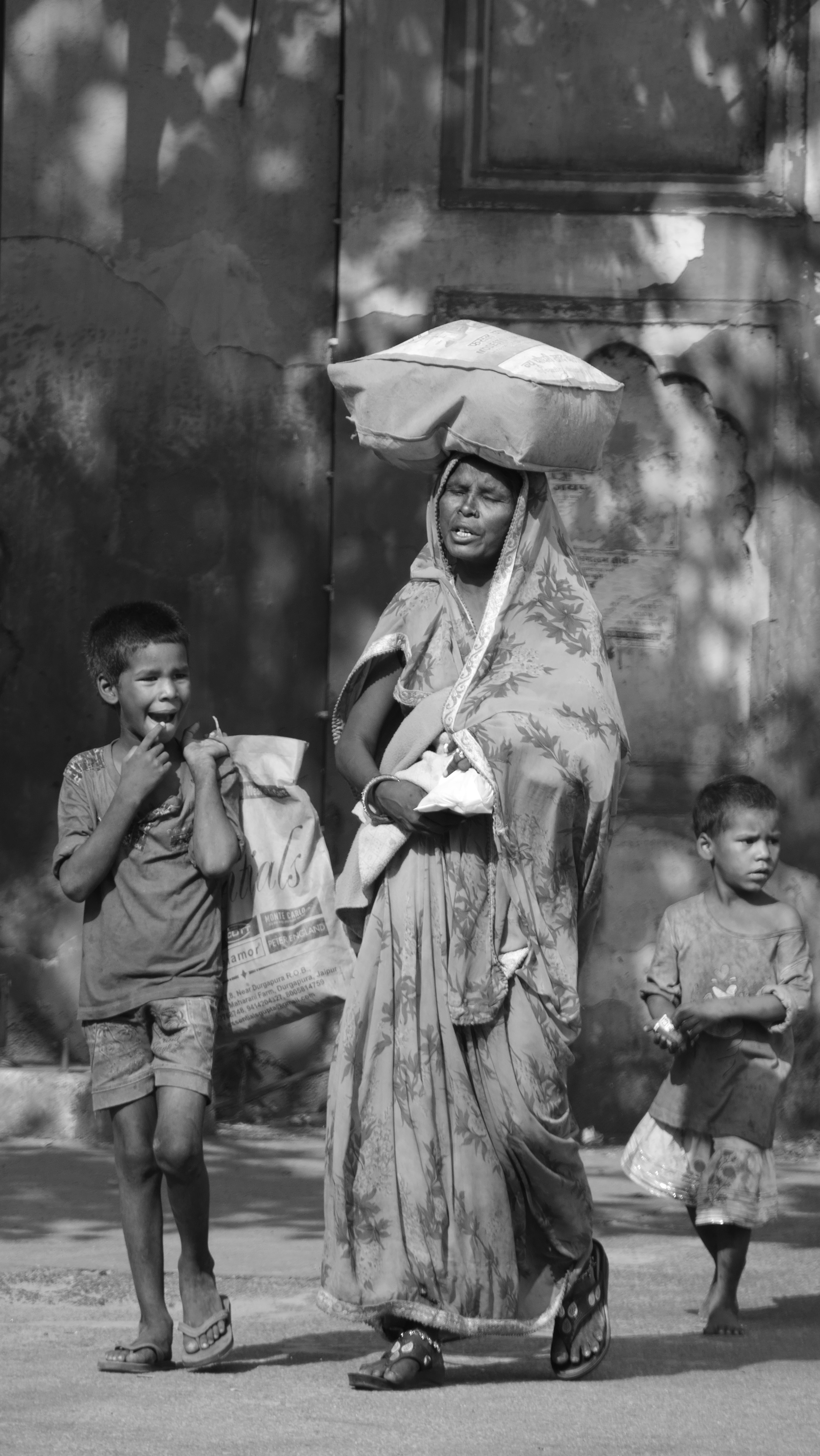 Mother and children on a sun-dappled street, silhouettes and cloth shadows
