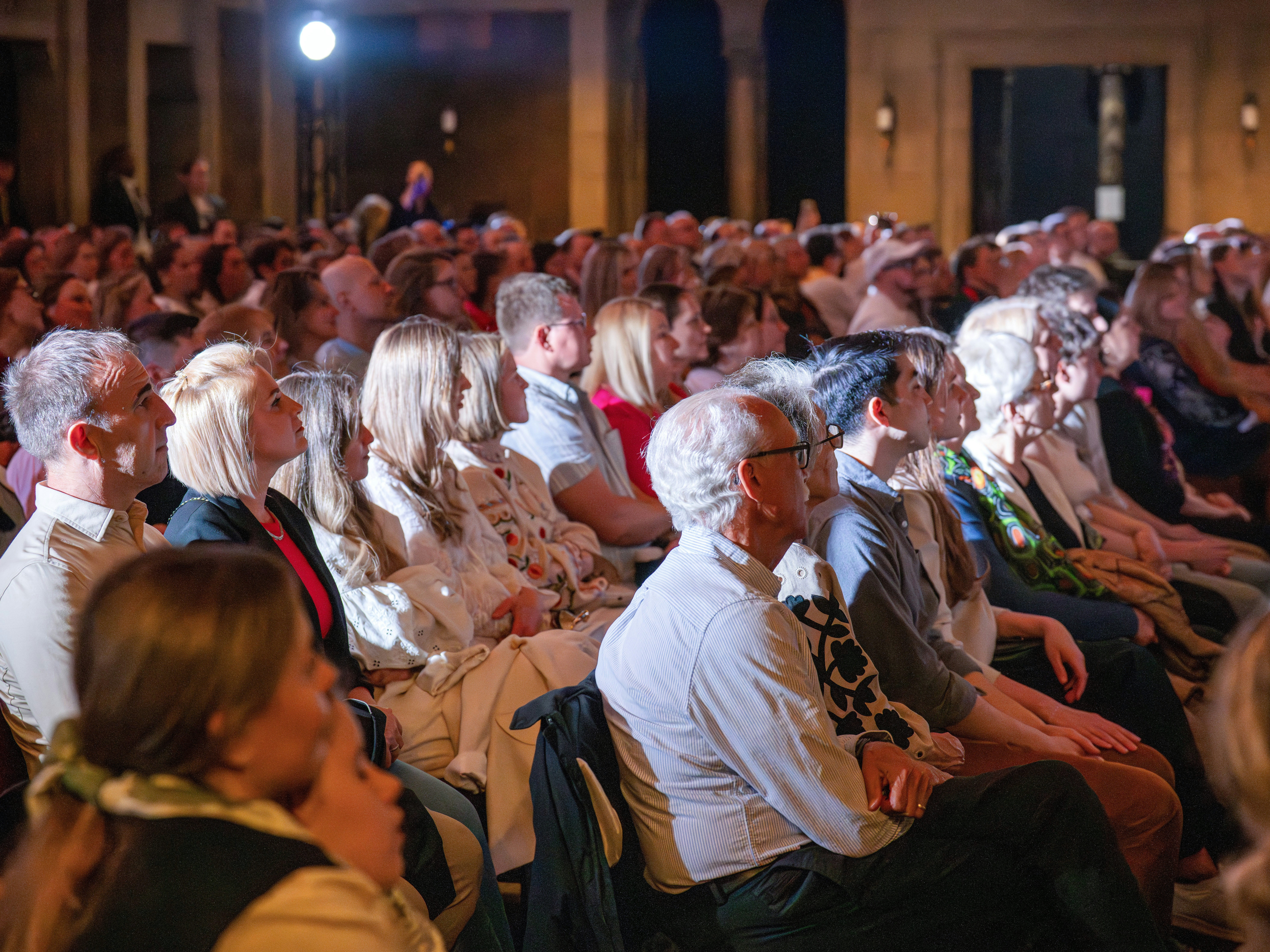 Silhouette of a Shared Moment: Audience in Soft Auditorium Light