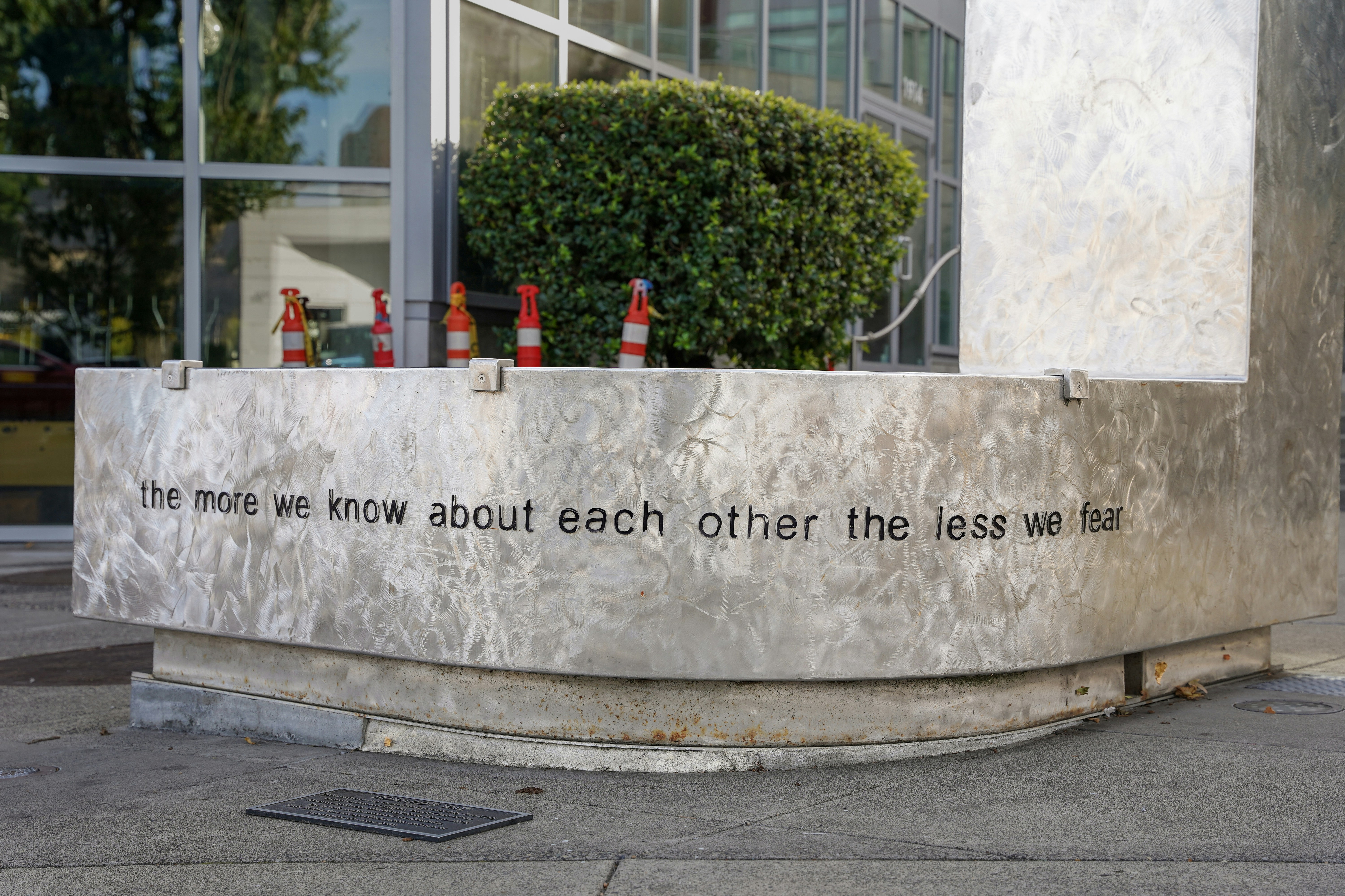 Stone Planter with Inscribed Quote and Orange Barriers at Office Exterior