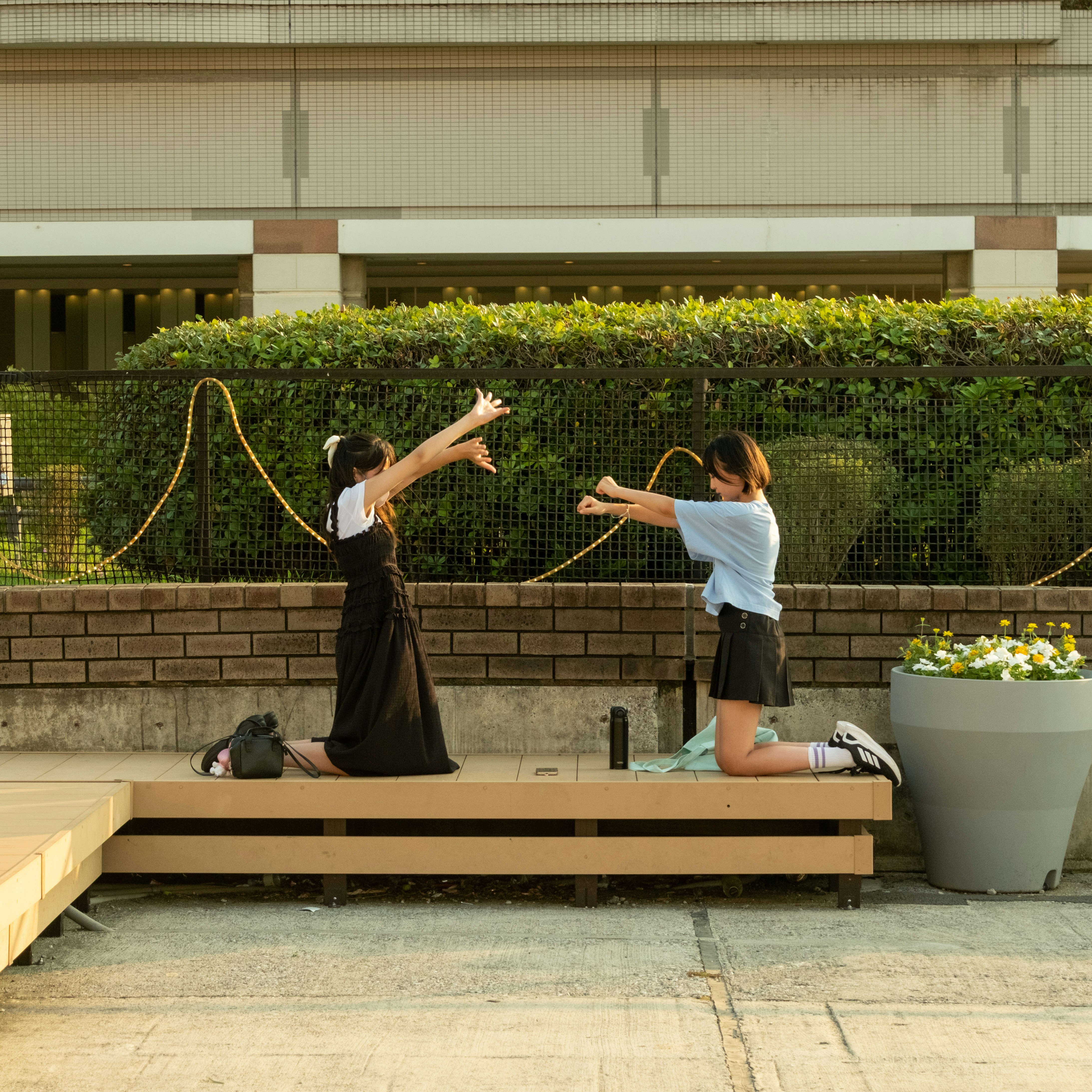Two dancers reach through a hazy rope to connect mid-air on a sunlit outdoor stage