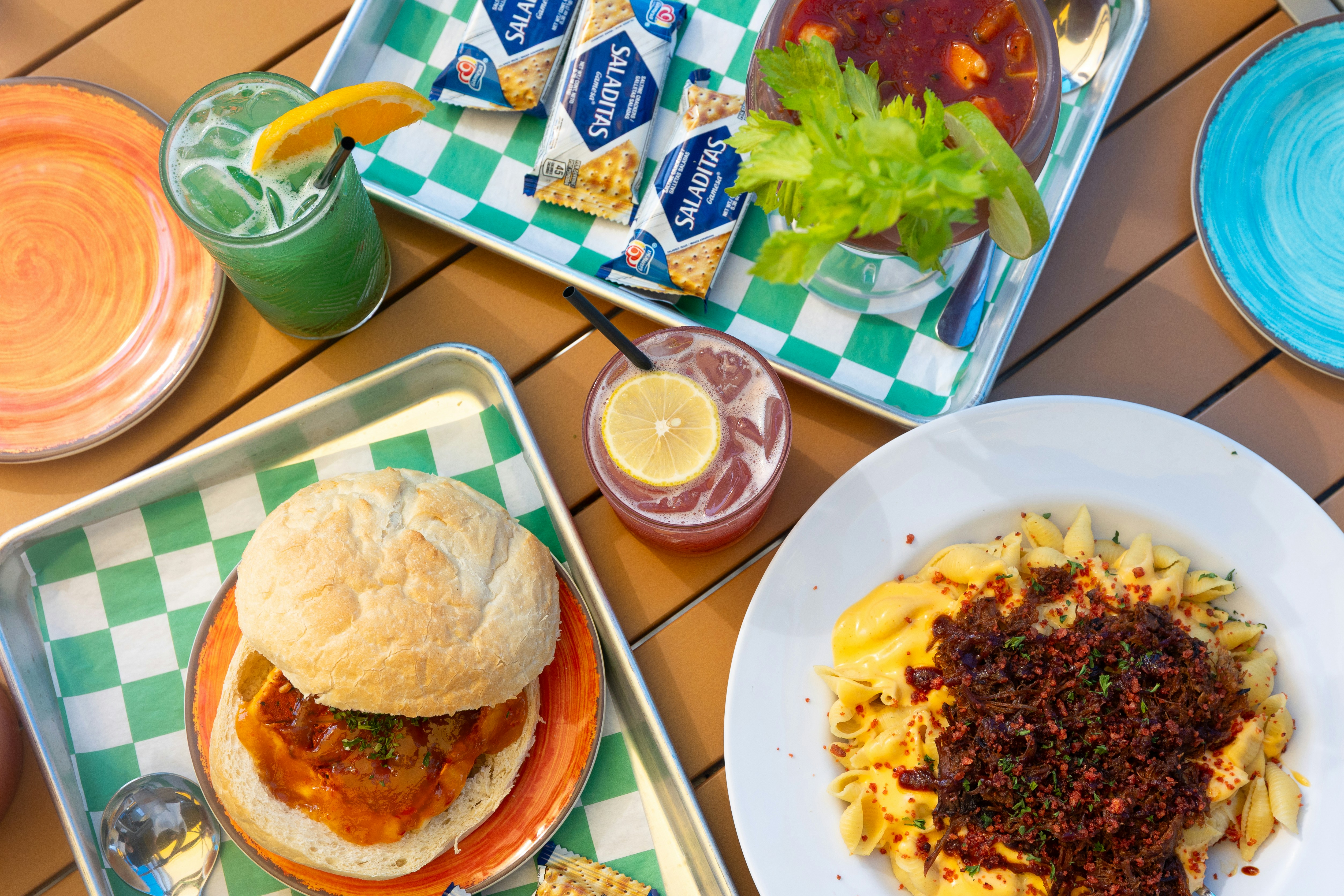 Sunlit Tray of Flavors: Picnic Table Feast with Burgers, Pasta, and Refreshing Drinks