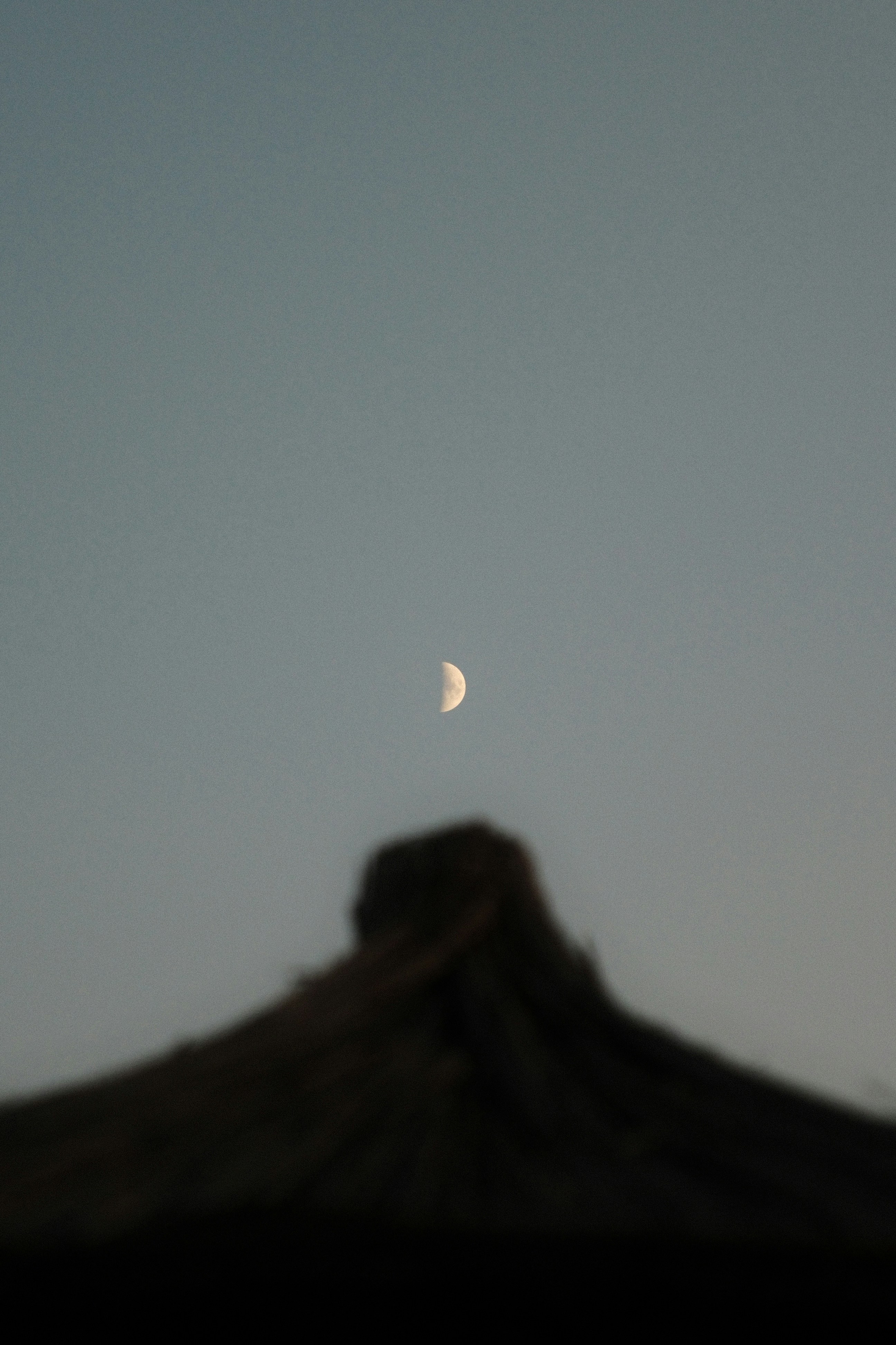 Moon above the silhouette: a lone lunar crescent over a distant peak
