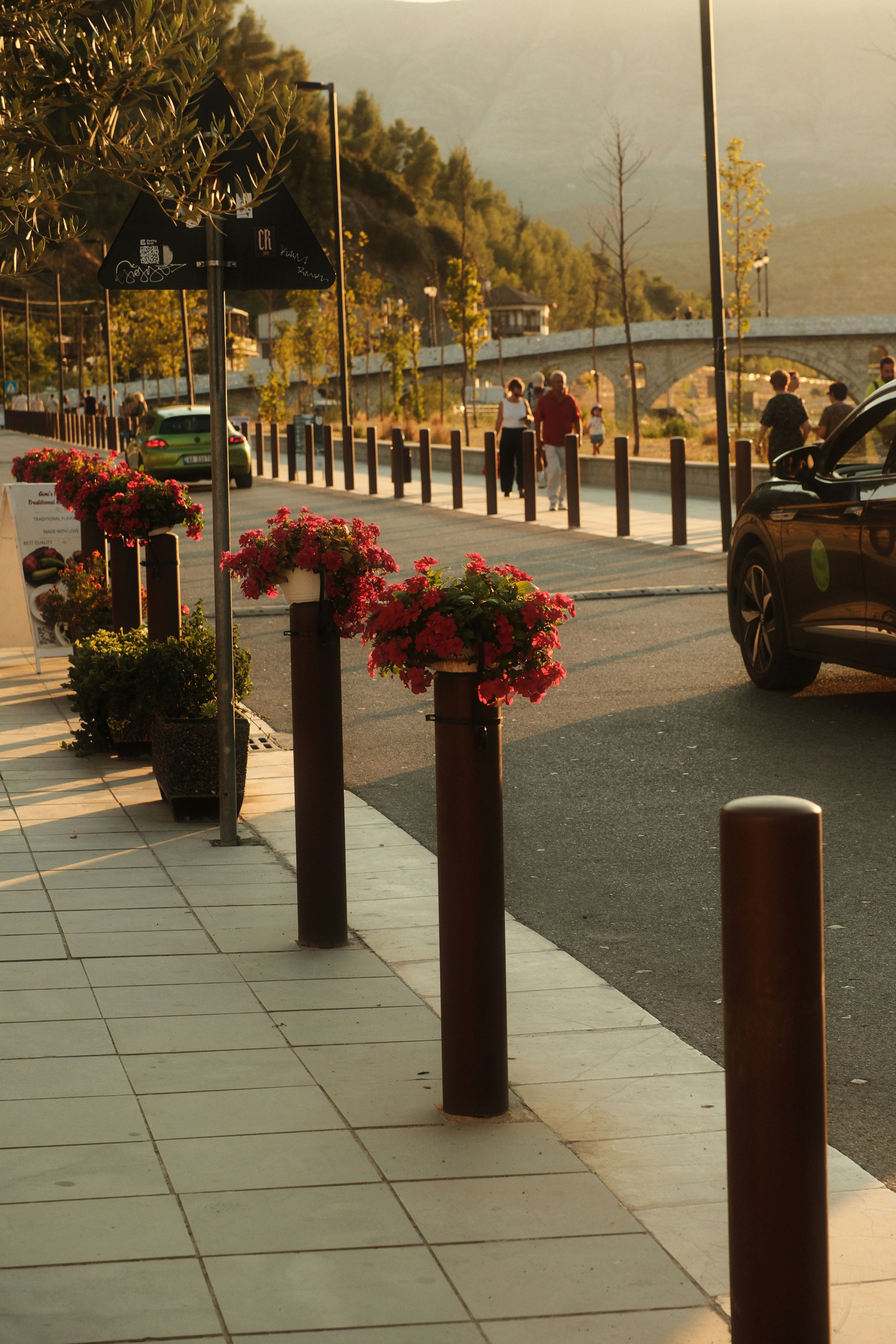 Sunlit Street Corridor: Flower-lined Posts and Pedestrians at Dusk