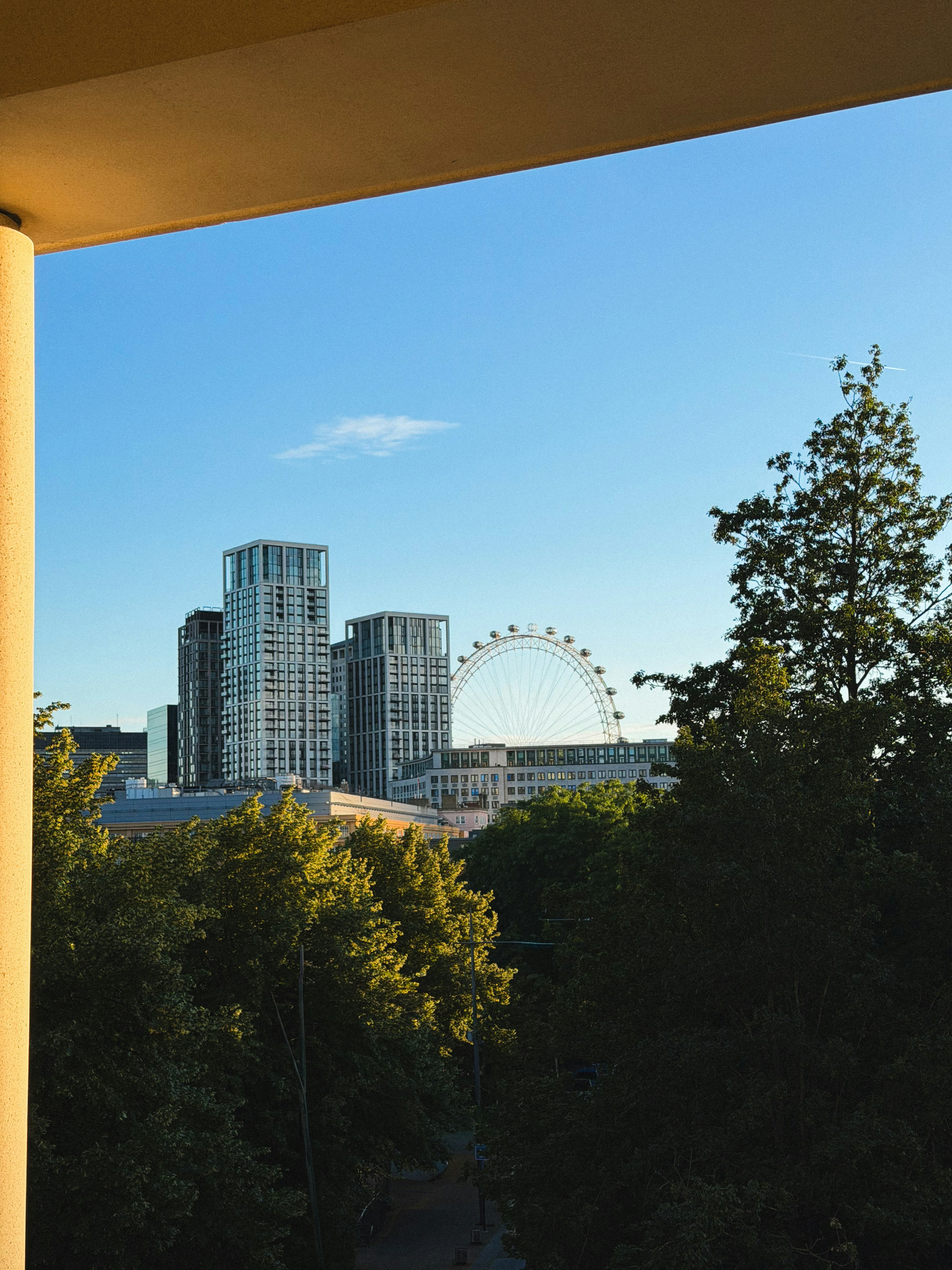 Cityscape Carousel: Ferris Wheel Beside Skyscrapers Framed by Trees
