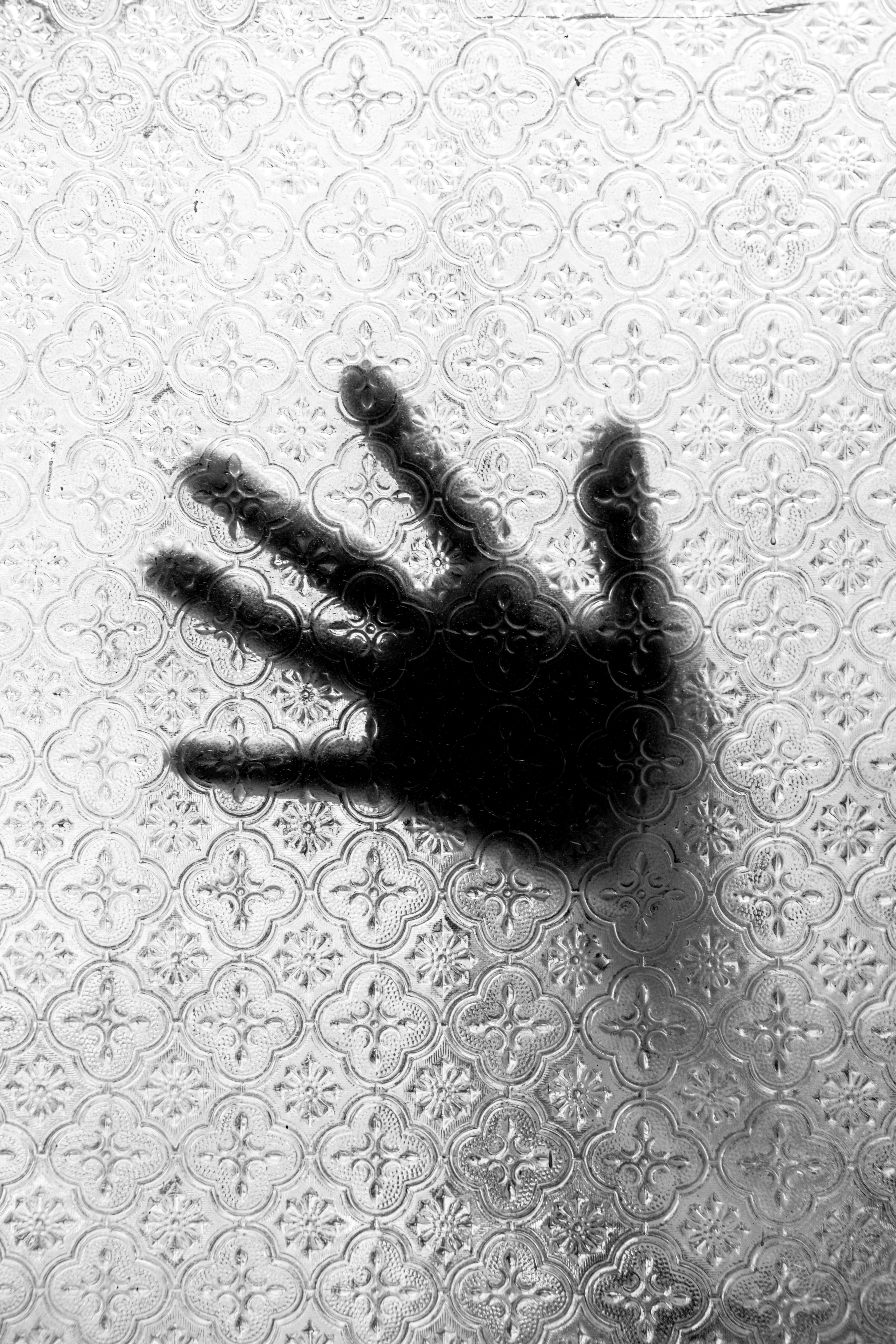 Shadowed Handprint on Frosted Glass: A Quiet Imprint in Patterned Light
