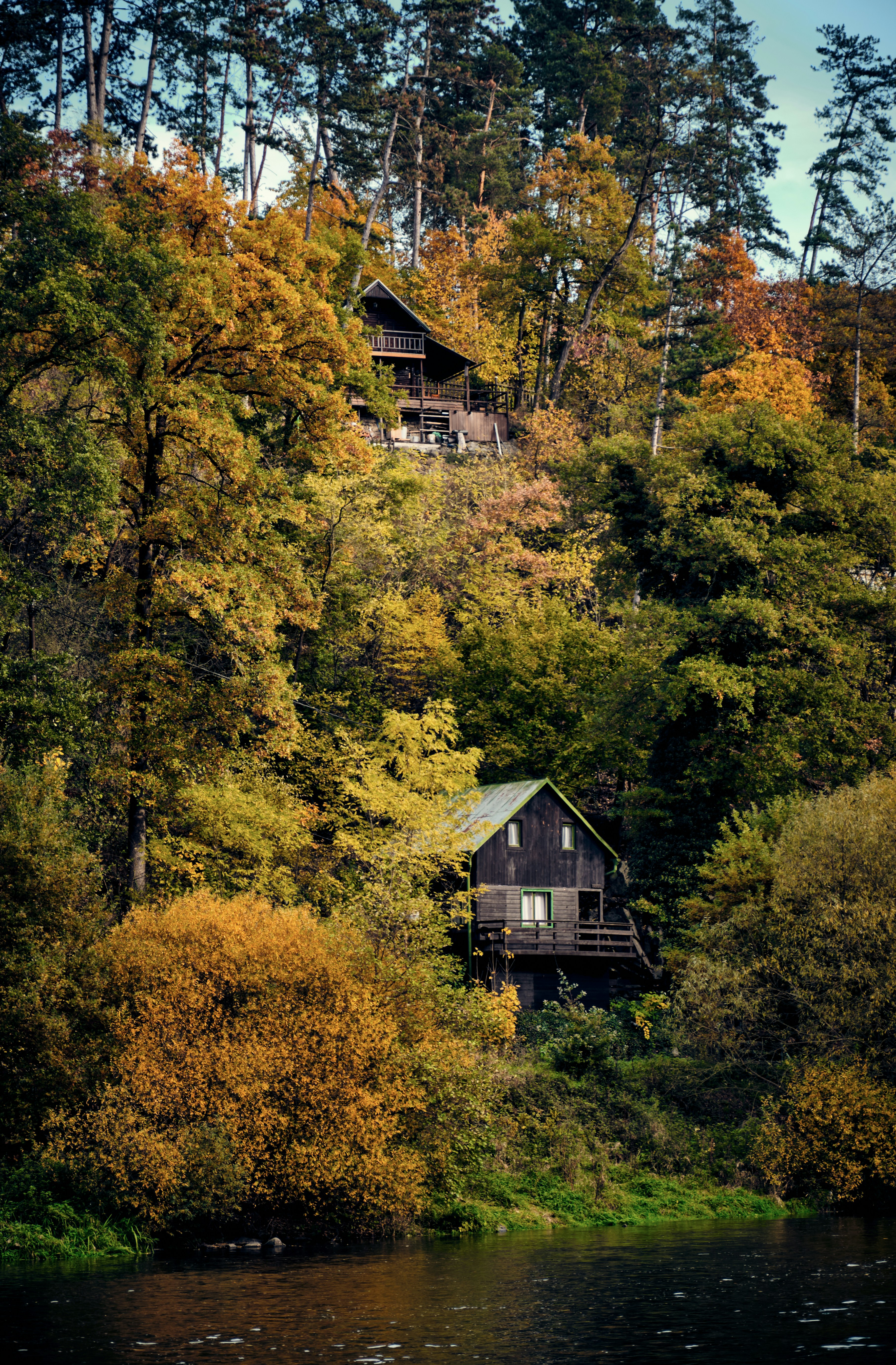 Autumn perch: a wooden cabin tucked amid fall-colored trees by the river