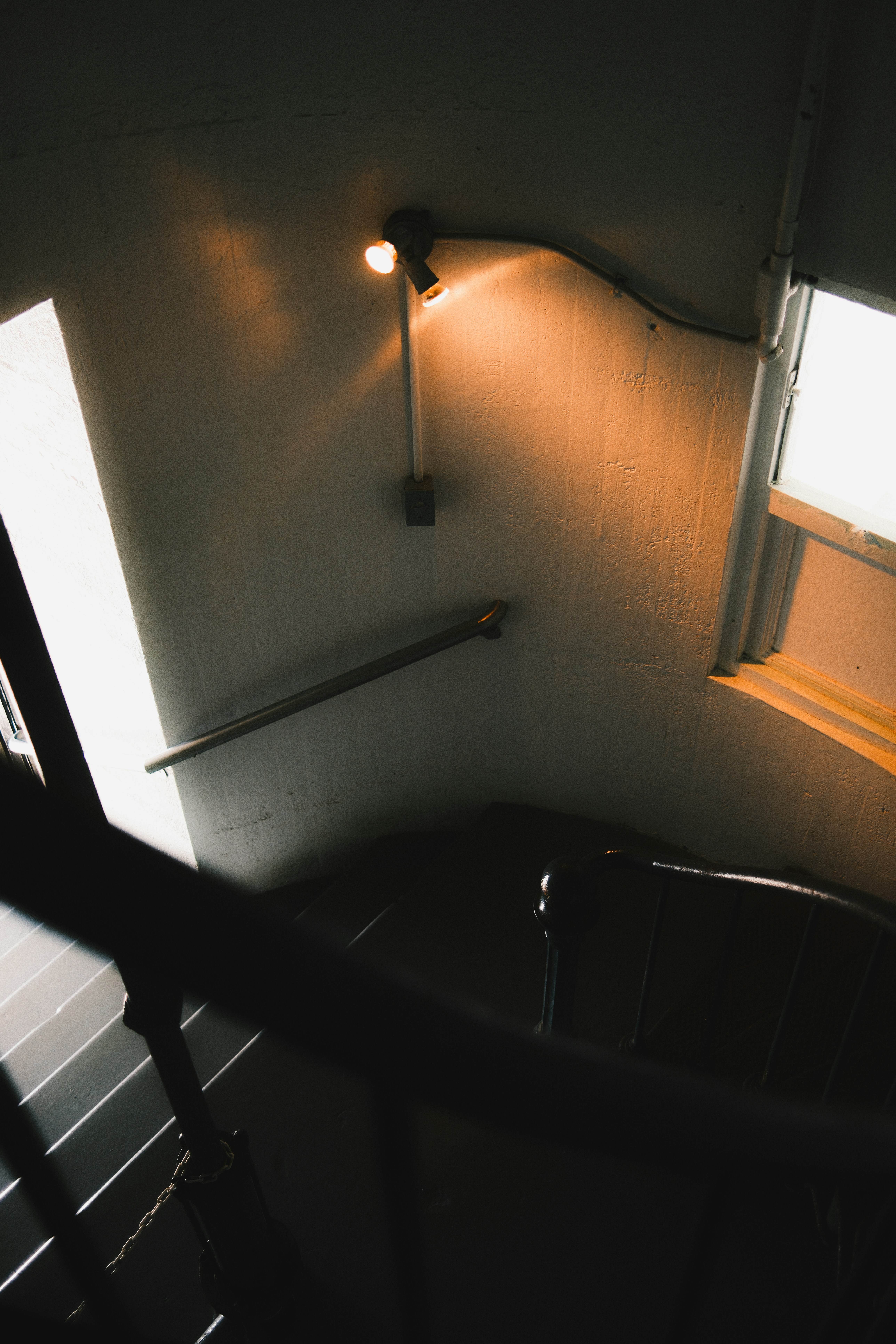 A dimly lit staircase with a warm wall lamp and metal handrail