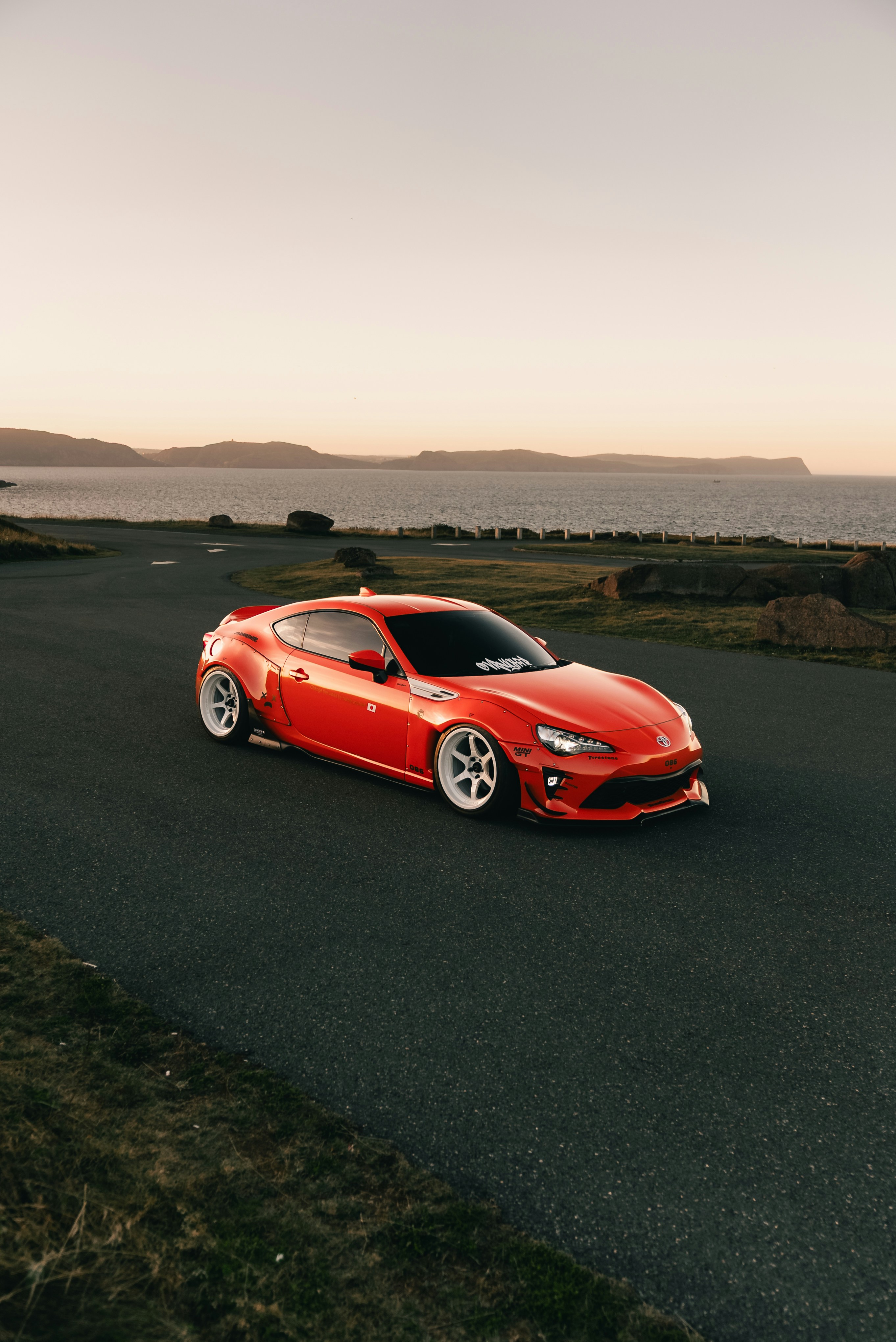 Red Sport Kouros: A Red Apex Car Poised on a Quiet Coastal Turn
