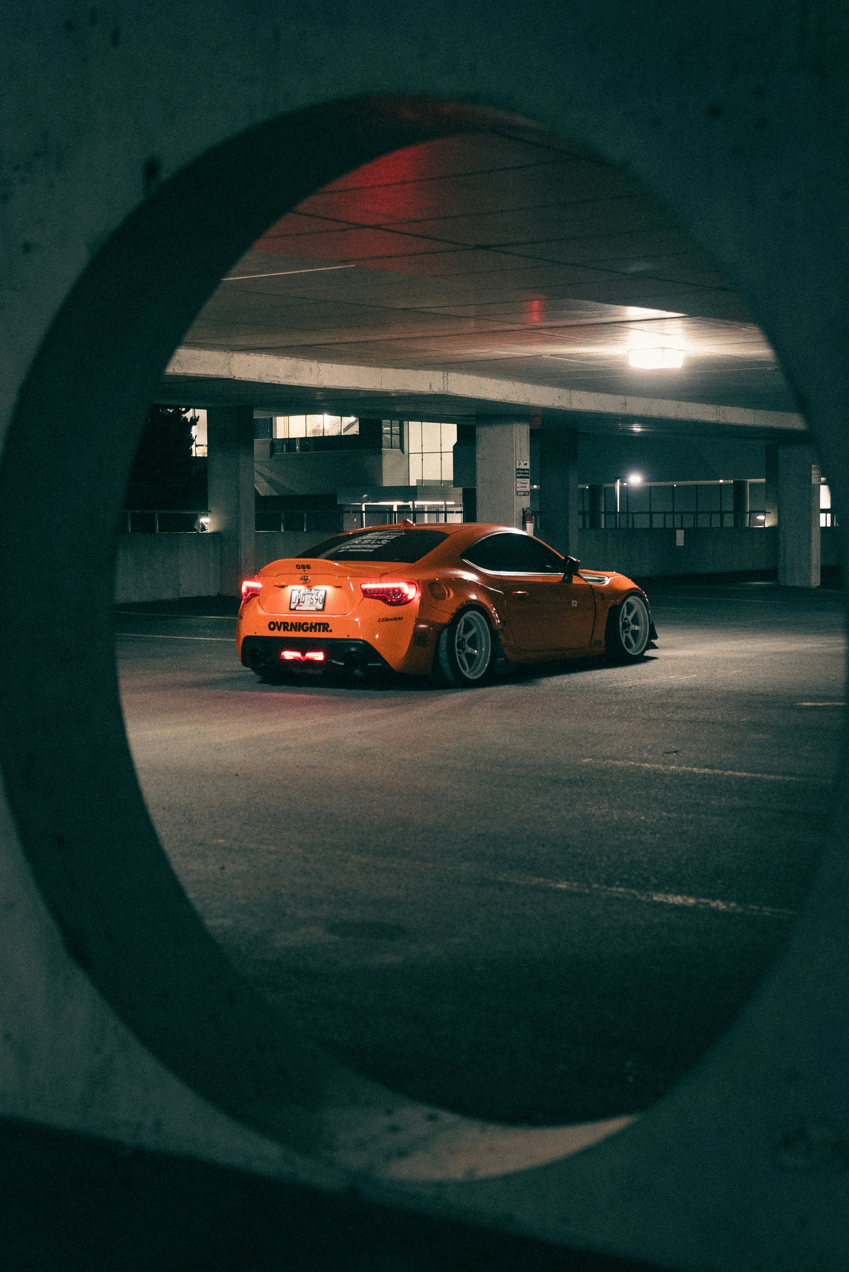 Orange Sports Car Framed Through a Circular Concrete Aperture