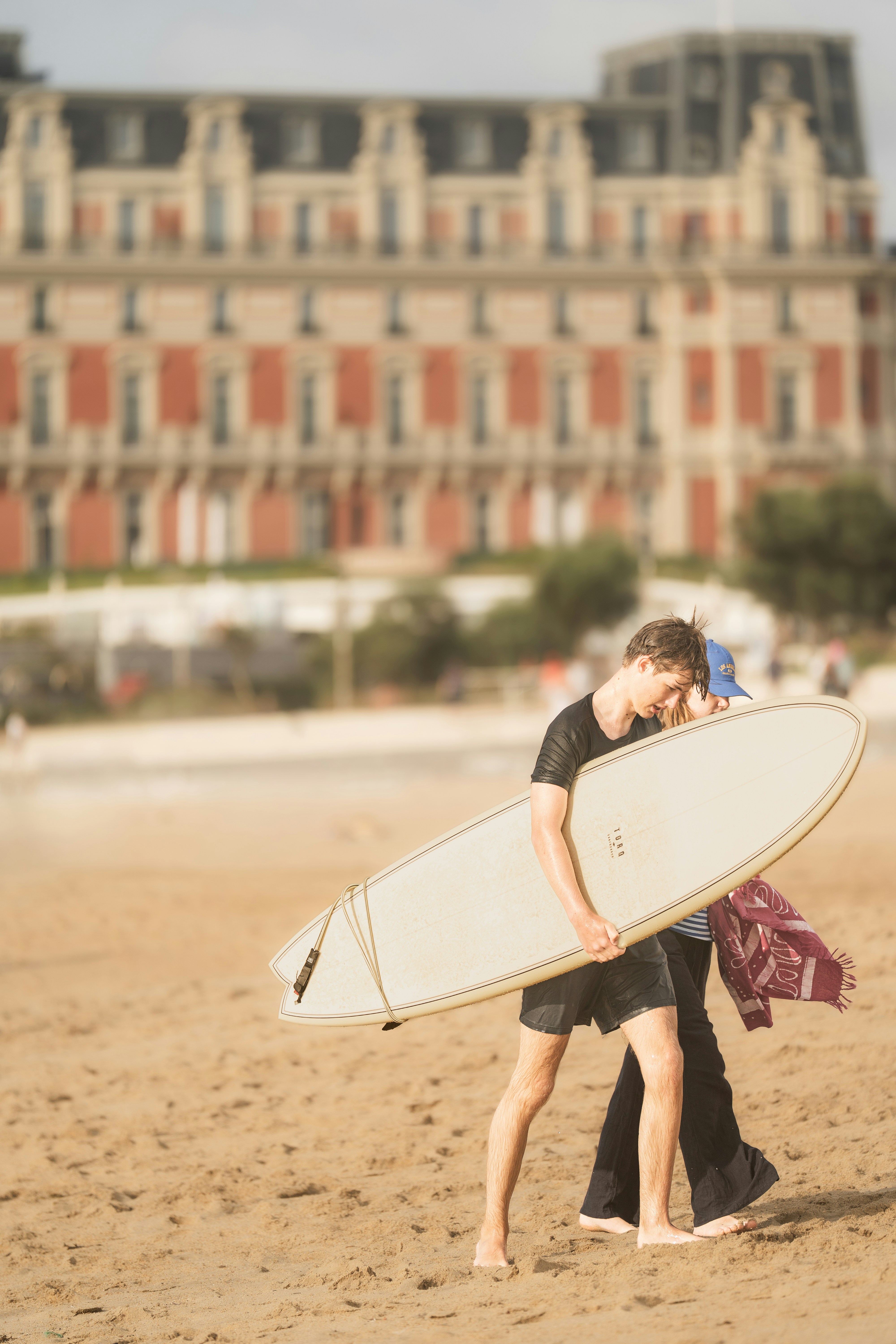 Surfboard Stride: a sunlit beach moment with a surfer and companion
