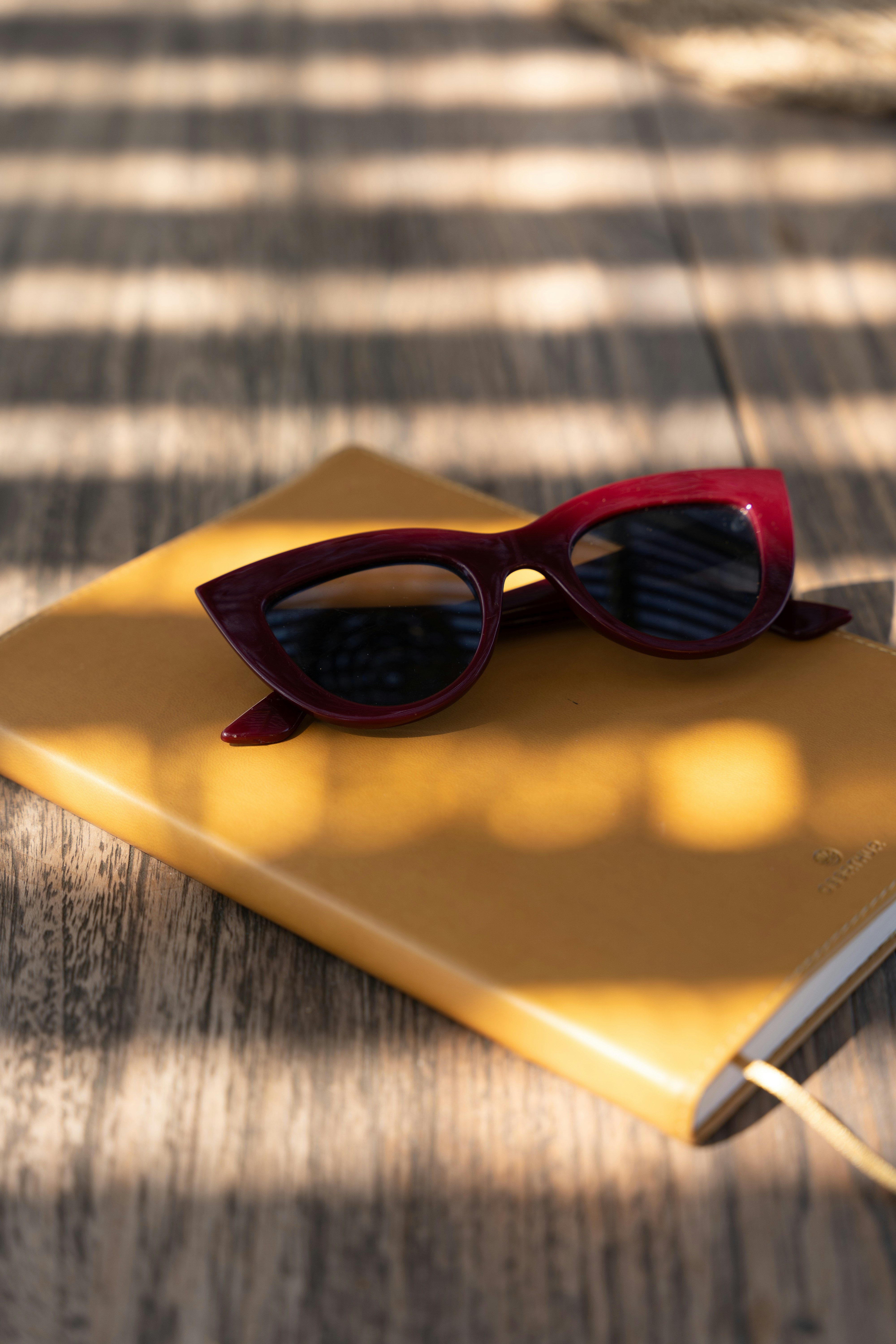 Red Frames, Golden Page: Sunglasses Resting on a Notebook
