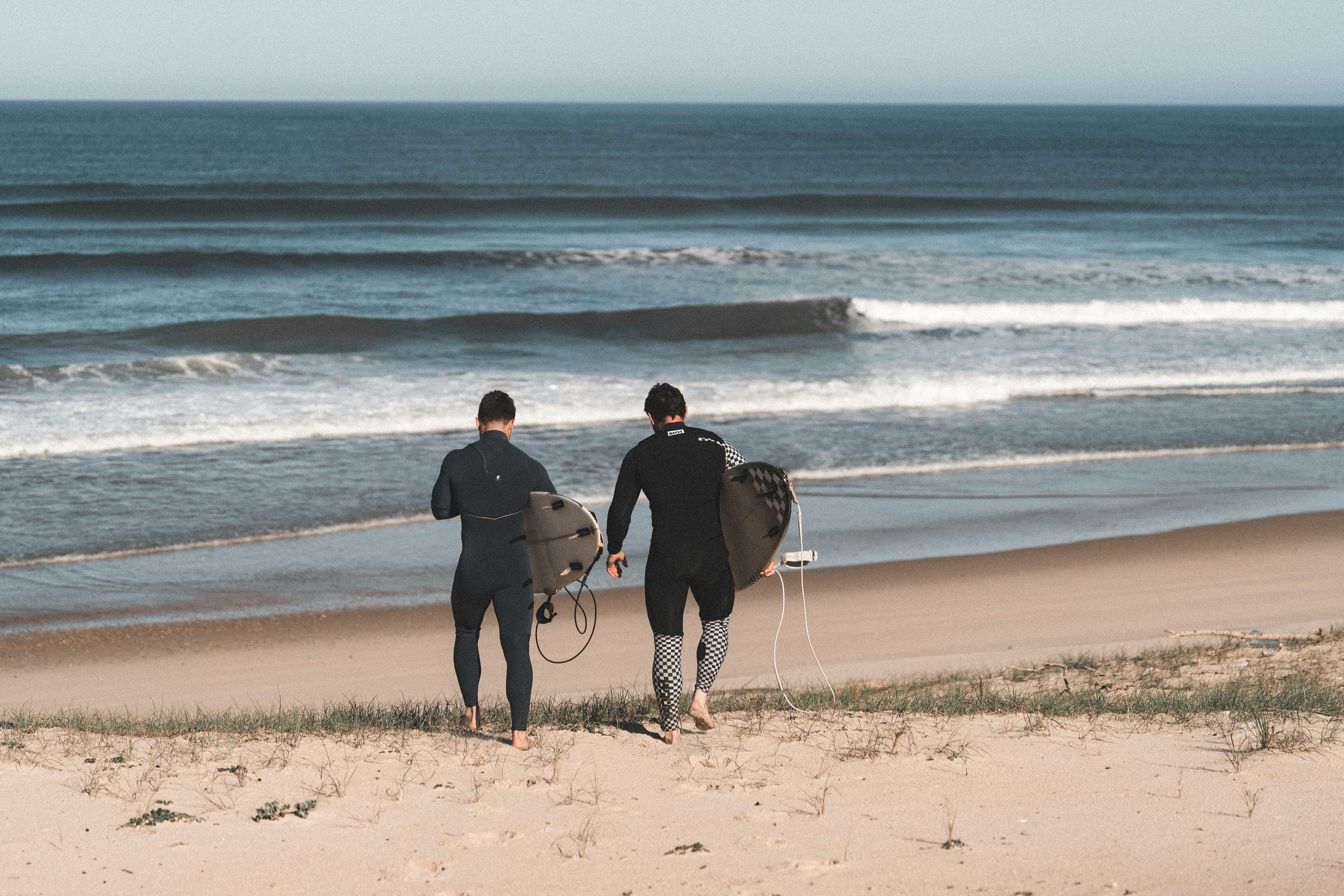 Two Surfers Heading Back from the Tide with Boards Under Arm