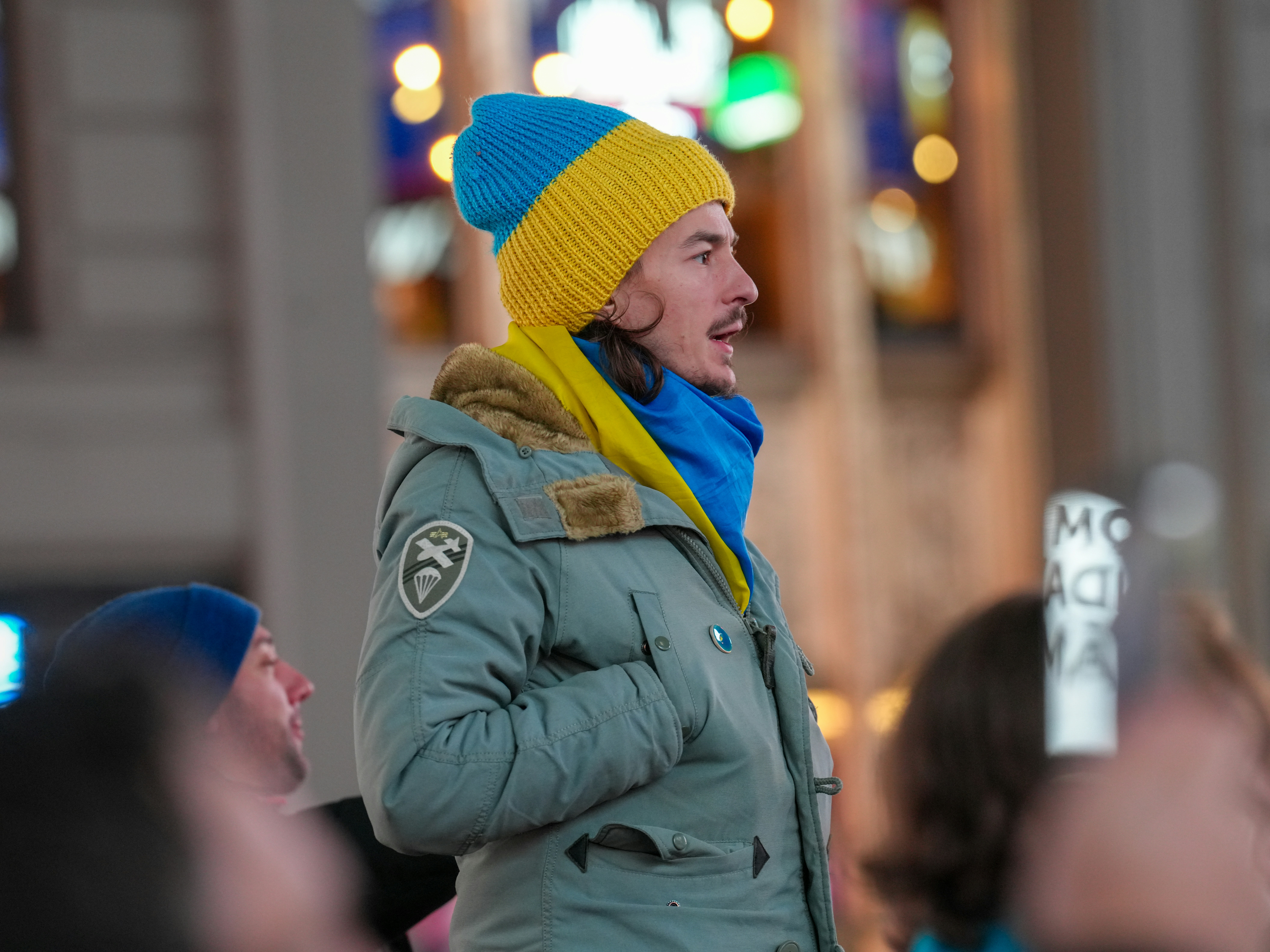Brightly dressed man in a winter crowd raises a scarfed conversation
