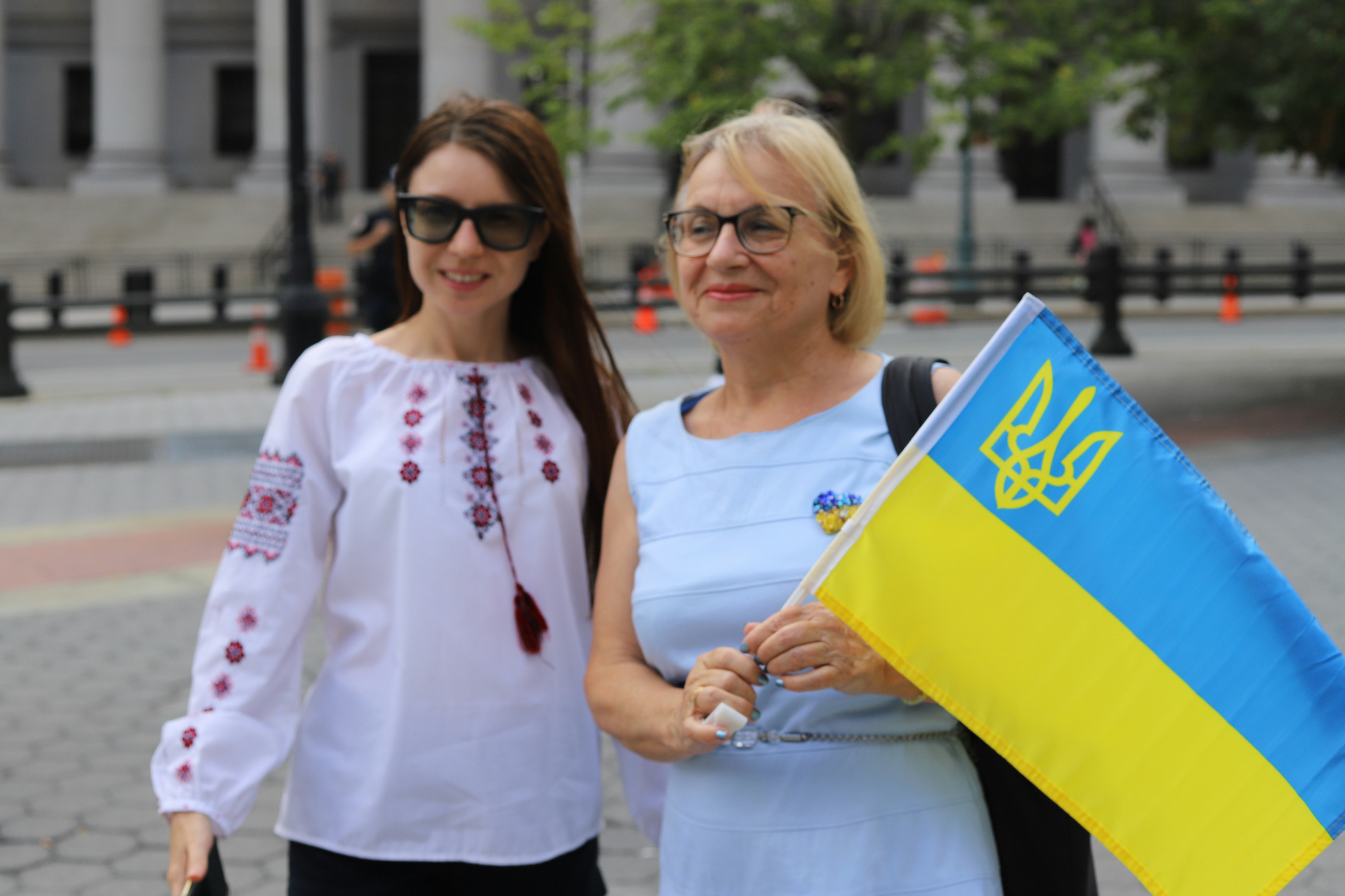 Two women in a public square, one waving a Ukrainian flag