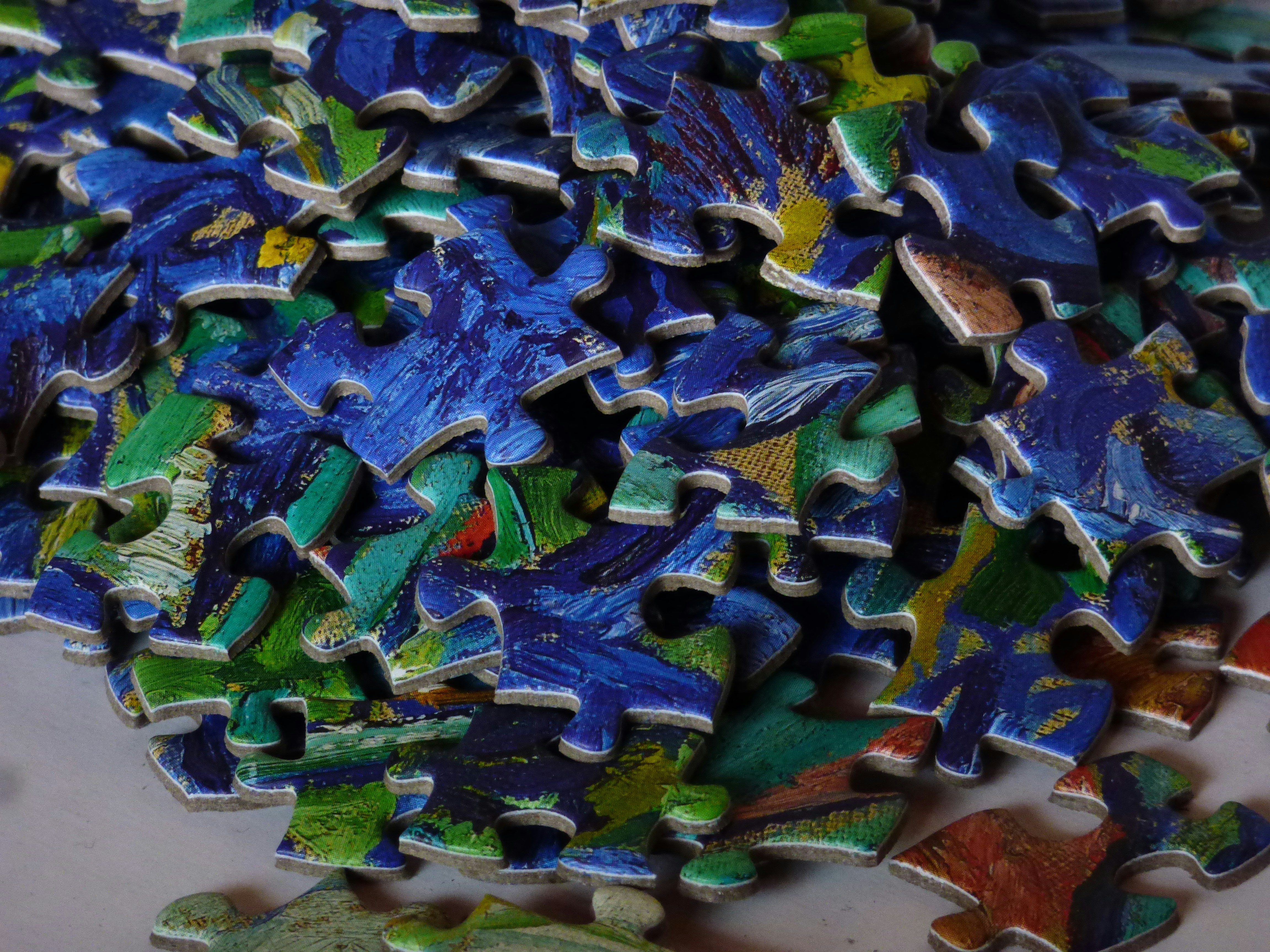 A pile of scattered jigsaw puzzle pieces with blue and green painted patterns