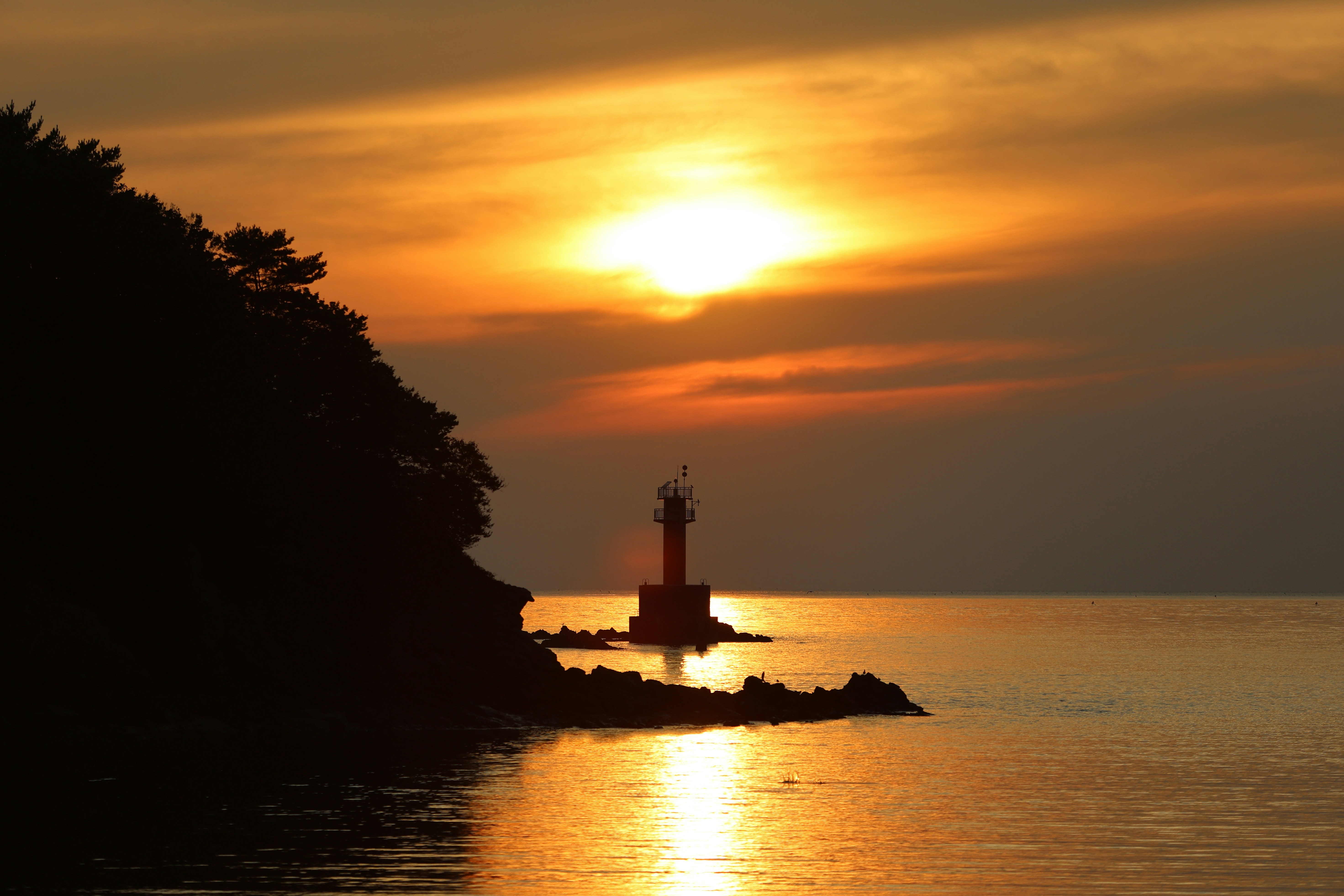 Lighthouse at Sunset: Silhouetted Breakwater Under a Golden Sky