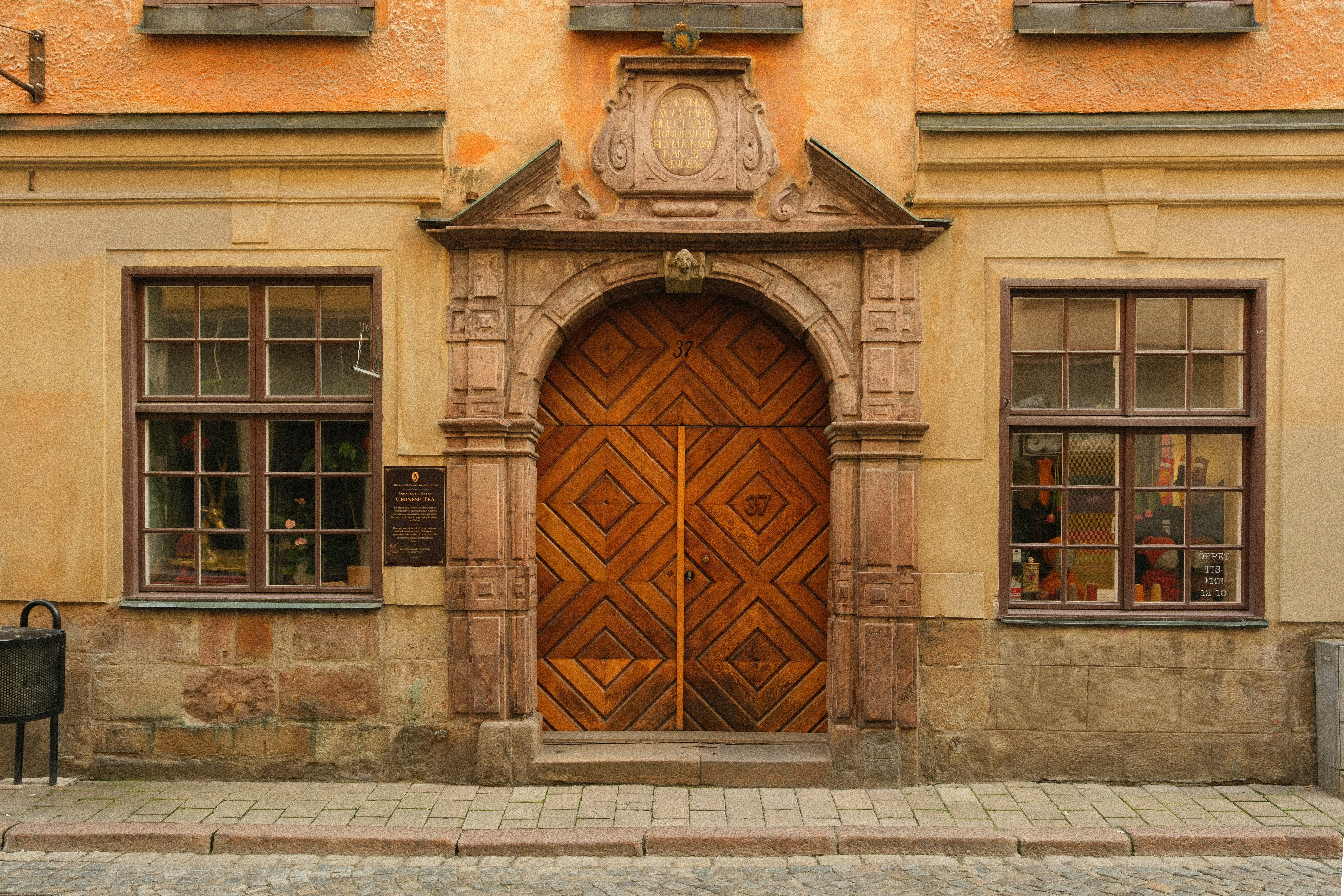 Ornate doorway between two shopfront windows in aged brick façade