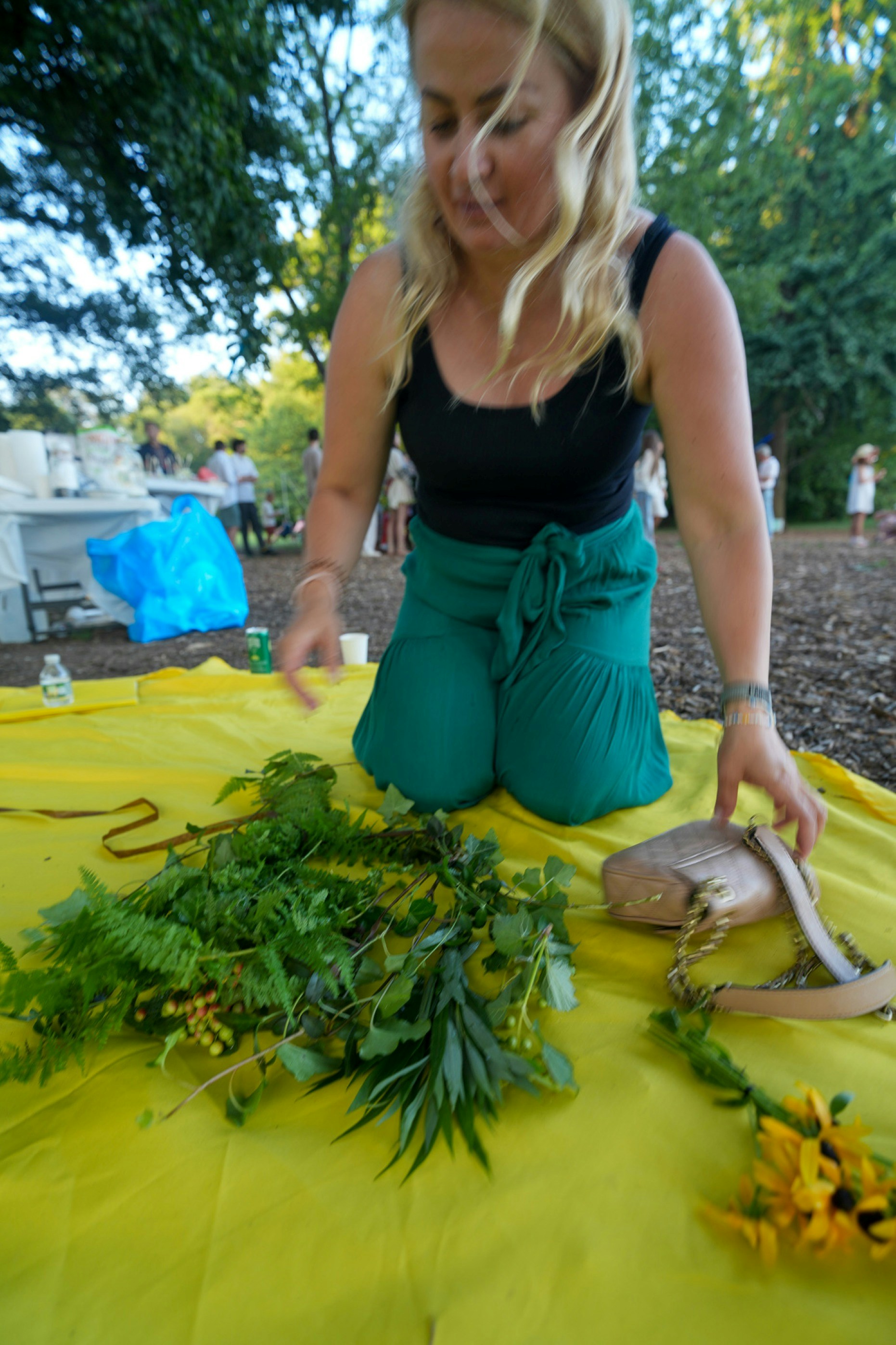 Kneeling at the Picnic: A Bouquet of Greens on a Vibrant Yellow Cloth