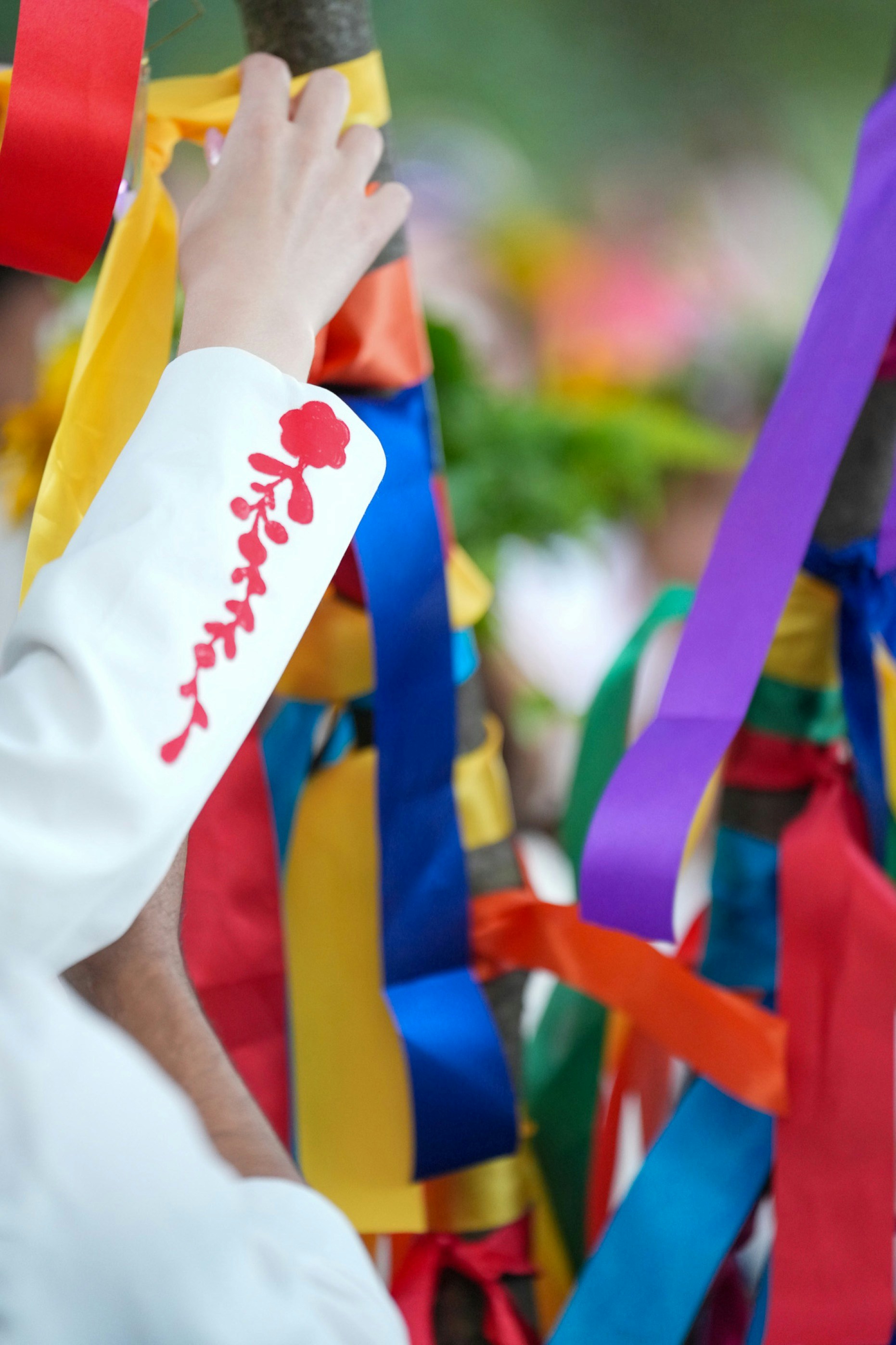 Colorful Strands of Celebration: Hands Reach for the Ribbon-Tied Pole