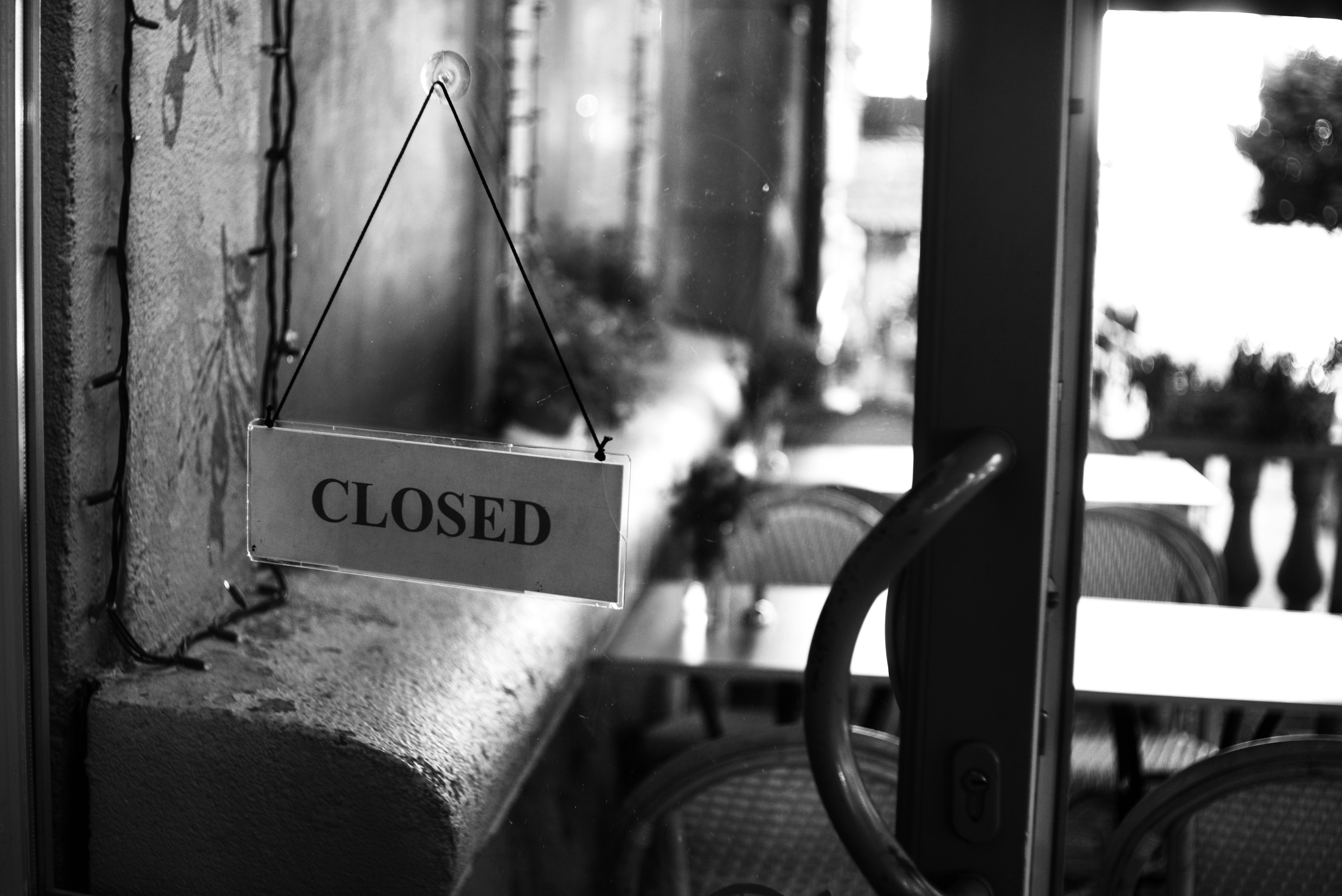 Quiet Closure: A Closed Sign Tethered to a Cafe Threshold