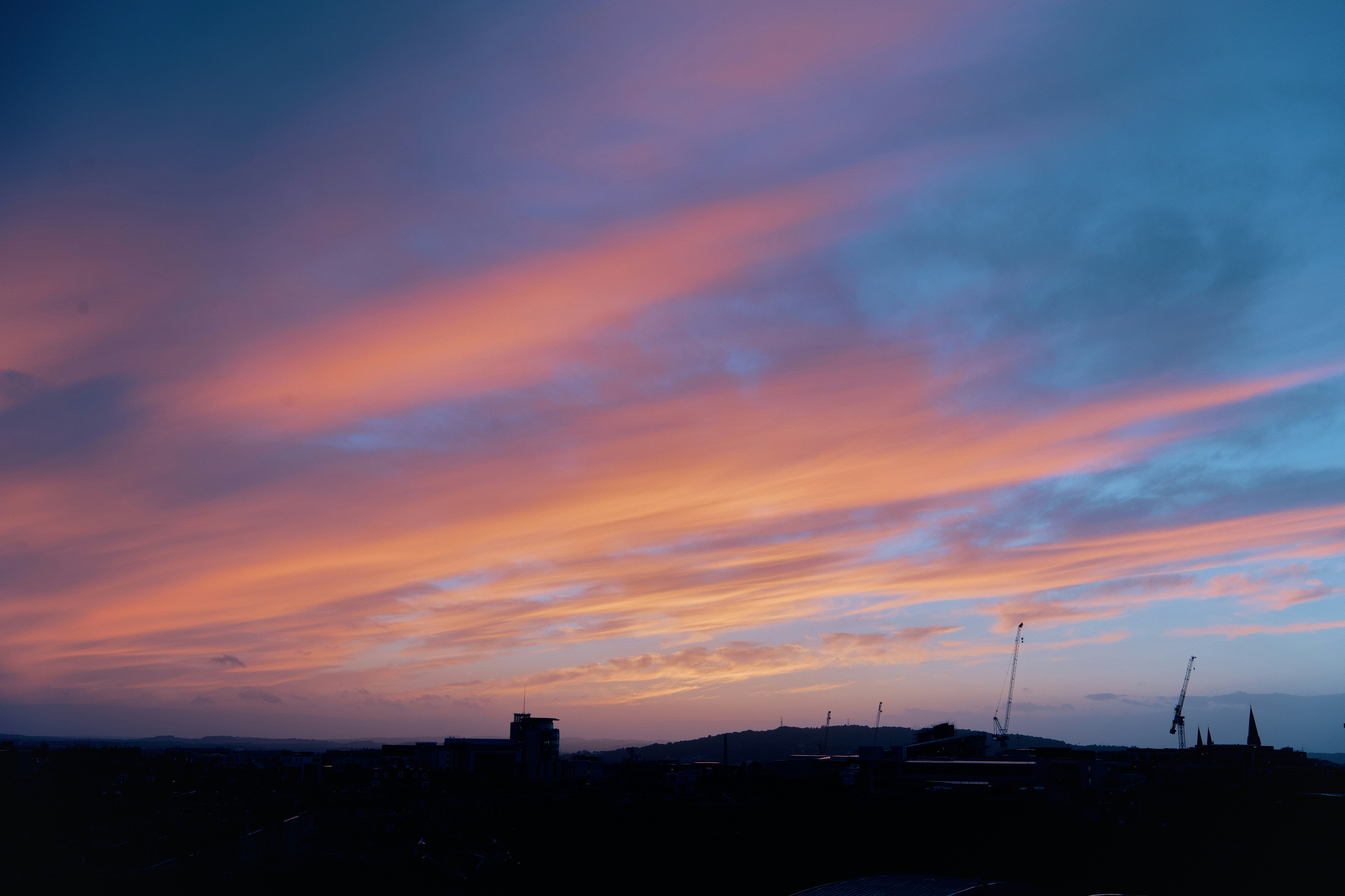 Cerulean Twilight: Clouds set ablaze over a quiet skyline