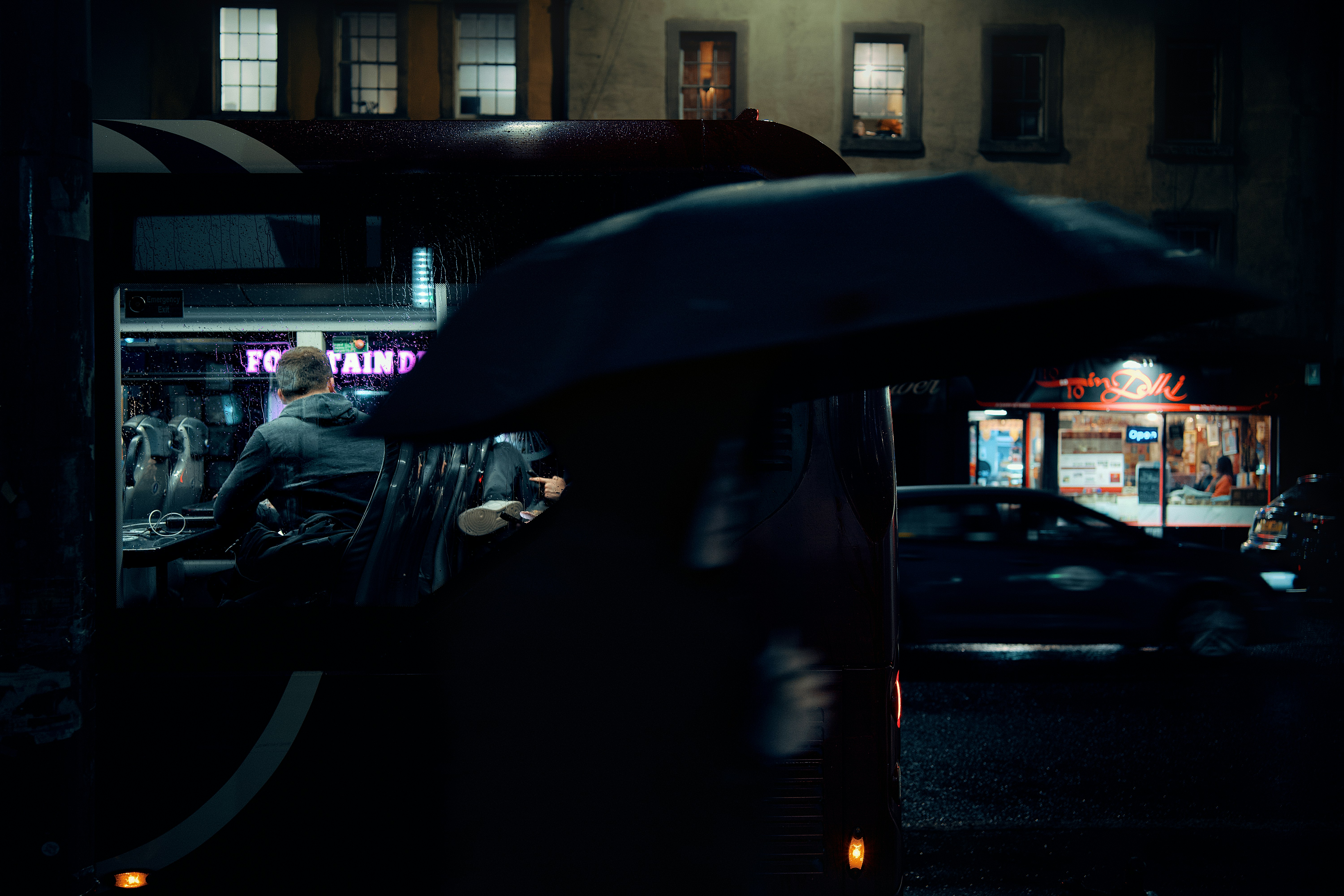 Midnight Bus Stop: Umbrella, Neon, and Rain